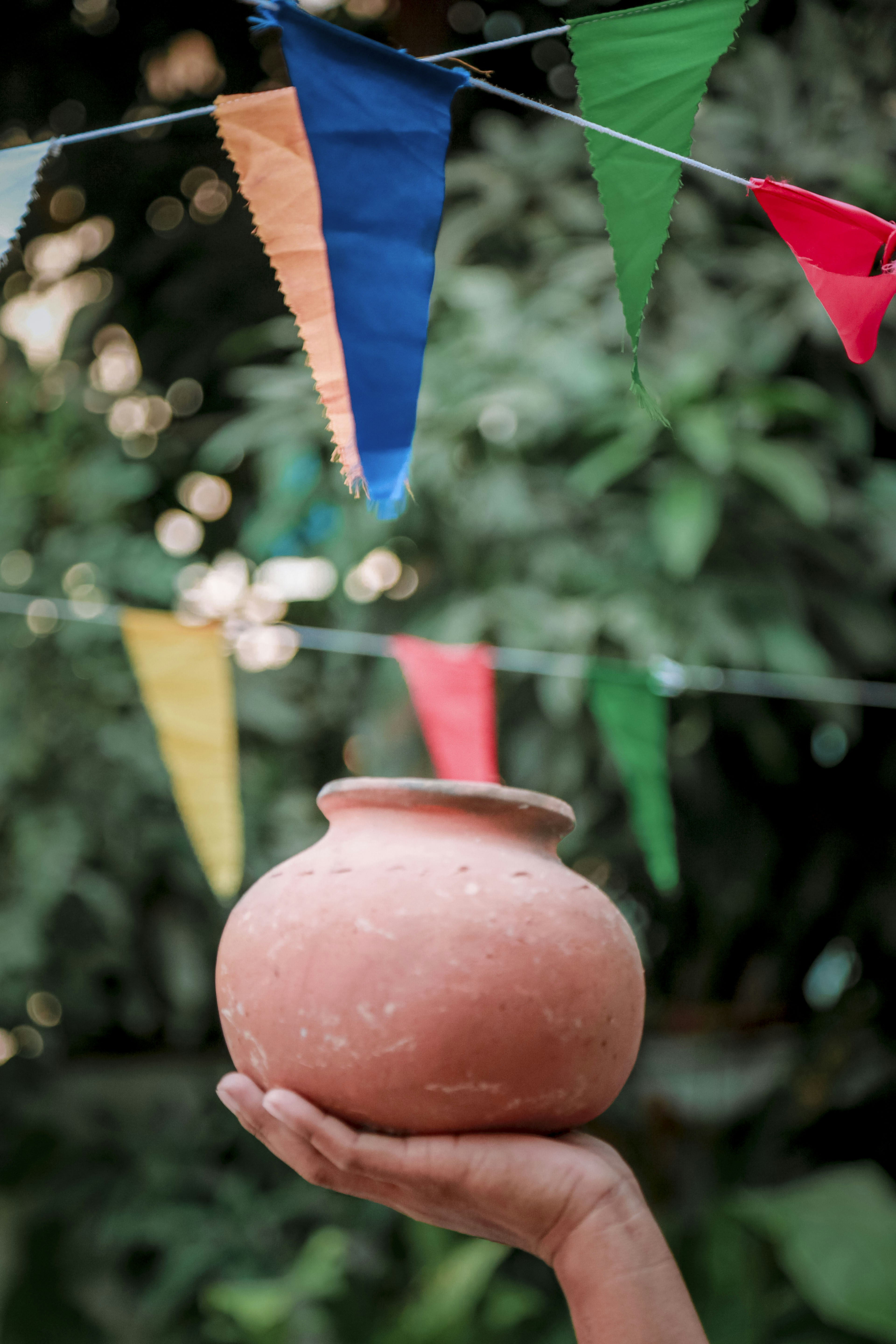 Amber Vessel in Hand Under Colorful Flags