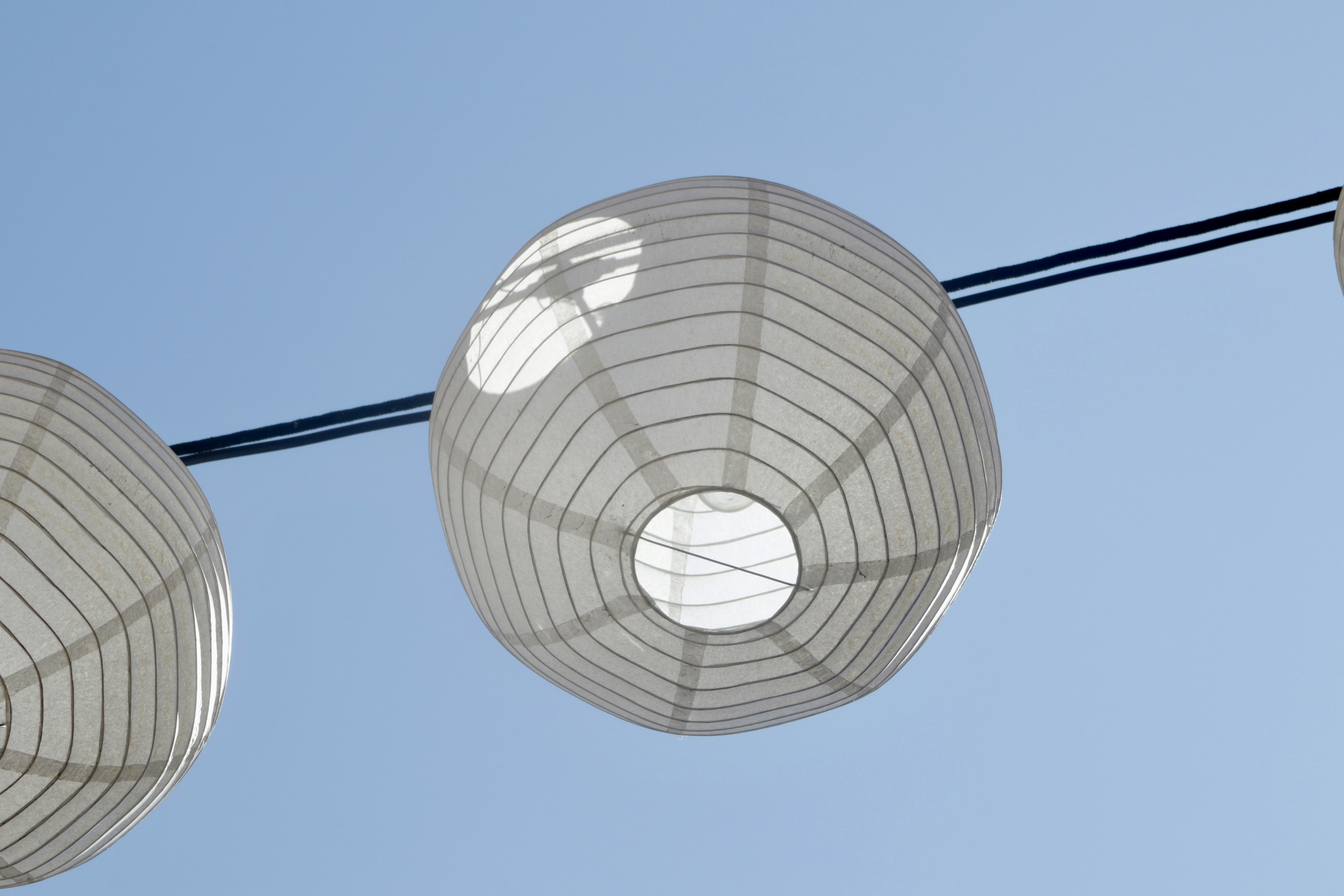 three lamps hanging from a wire against a blue sky
