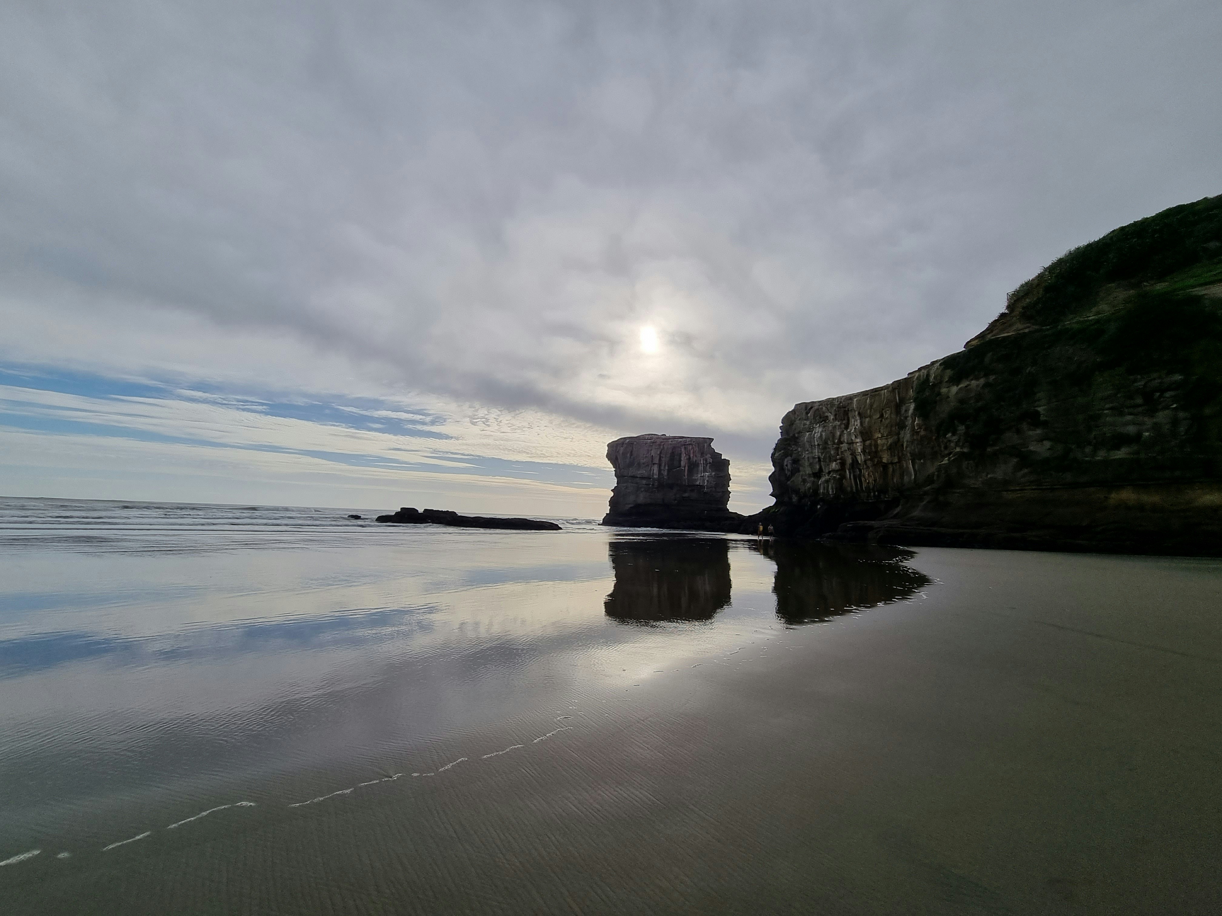 A beach with a rock outcropping in the distance photo – Free Rock Image ...