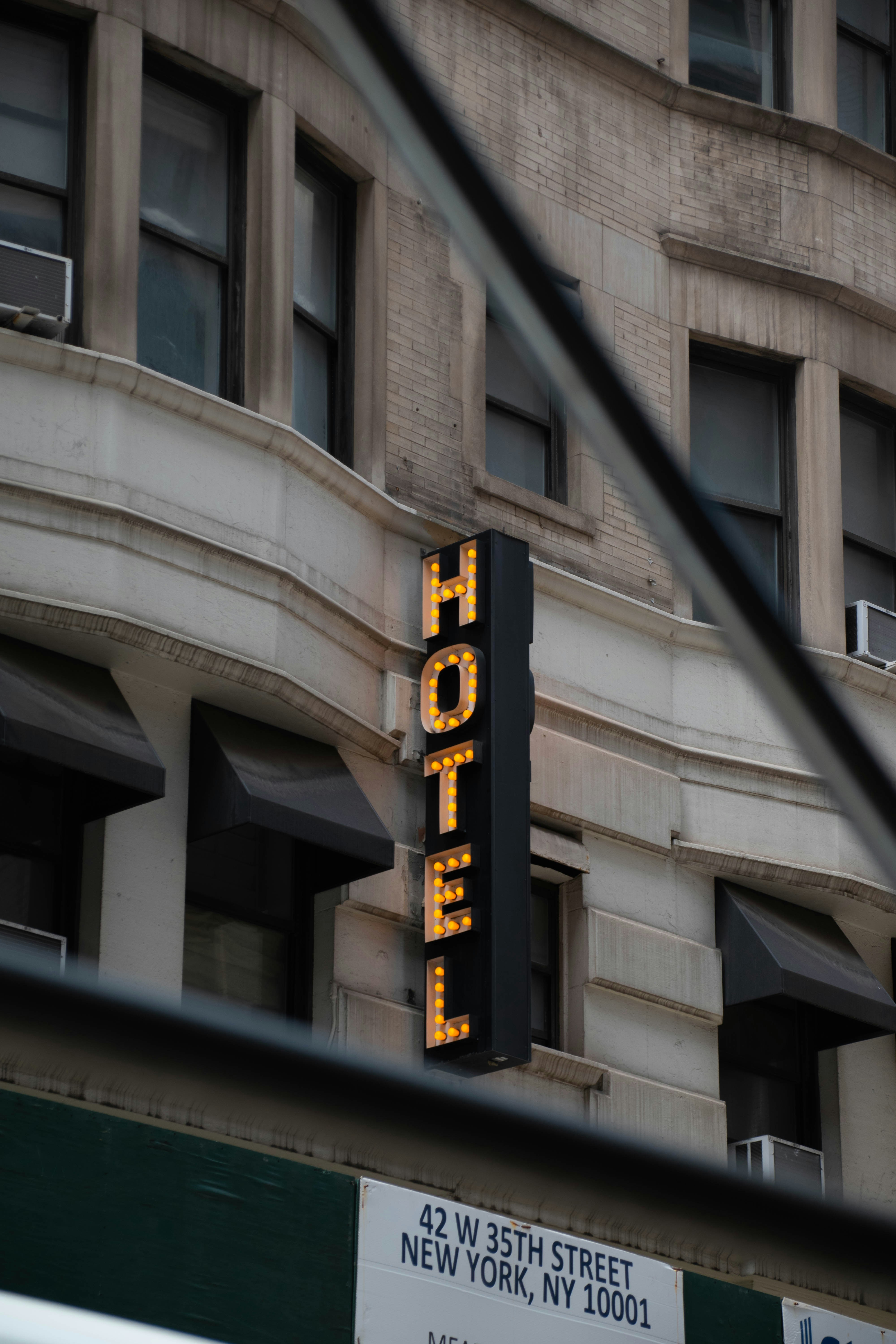 Vertical Neon Hotel Sign Framed by Urban Geometry