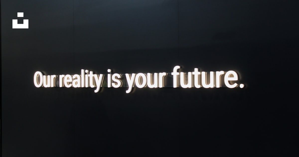 A Black Wall With A Neon Sign That Says Our Reality Is Your Future