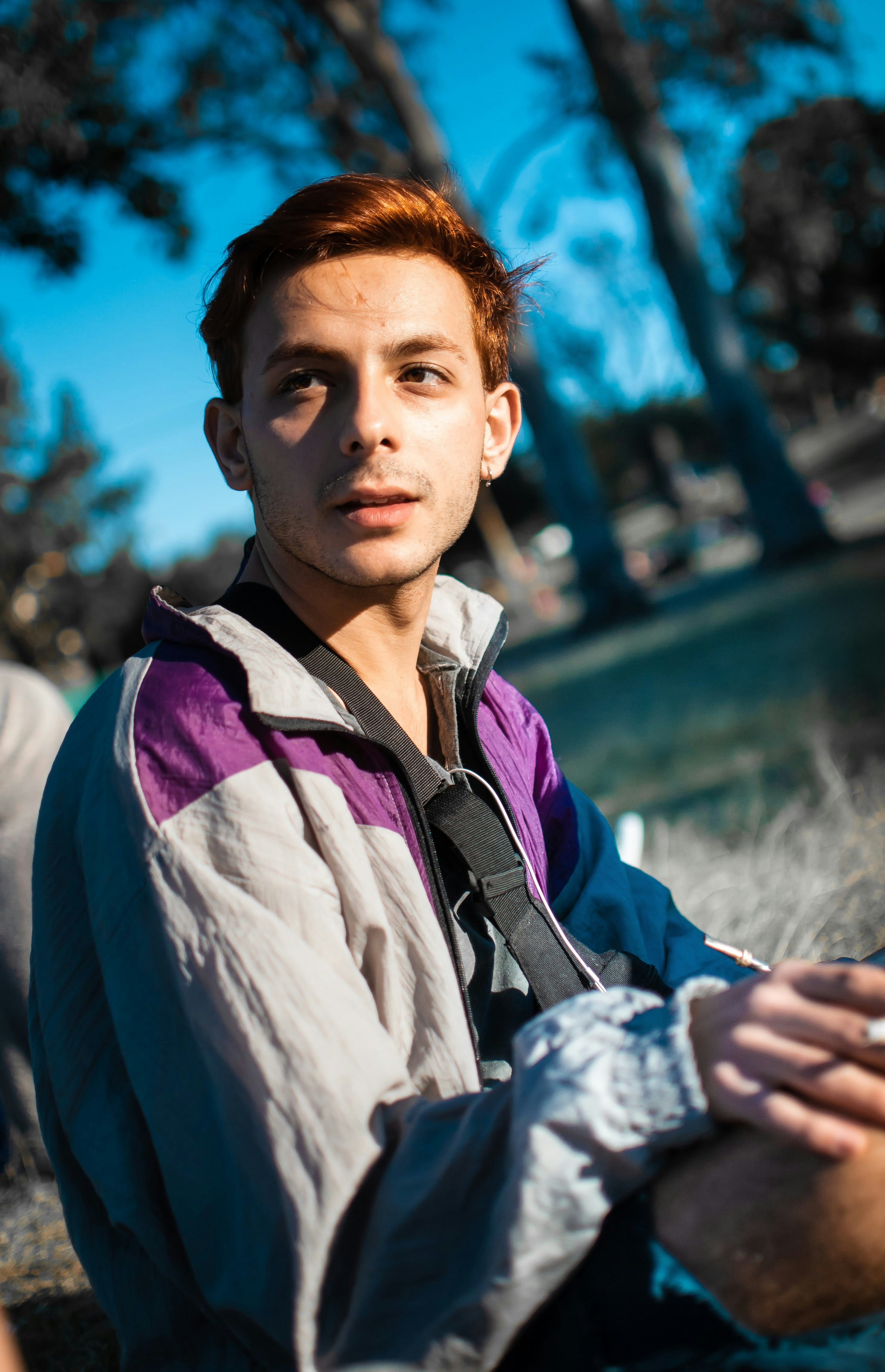 a young man sitting on the ground in a park
