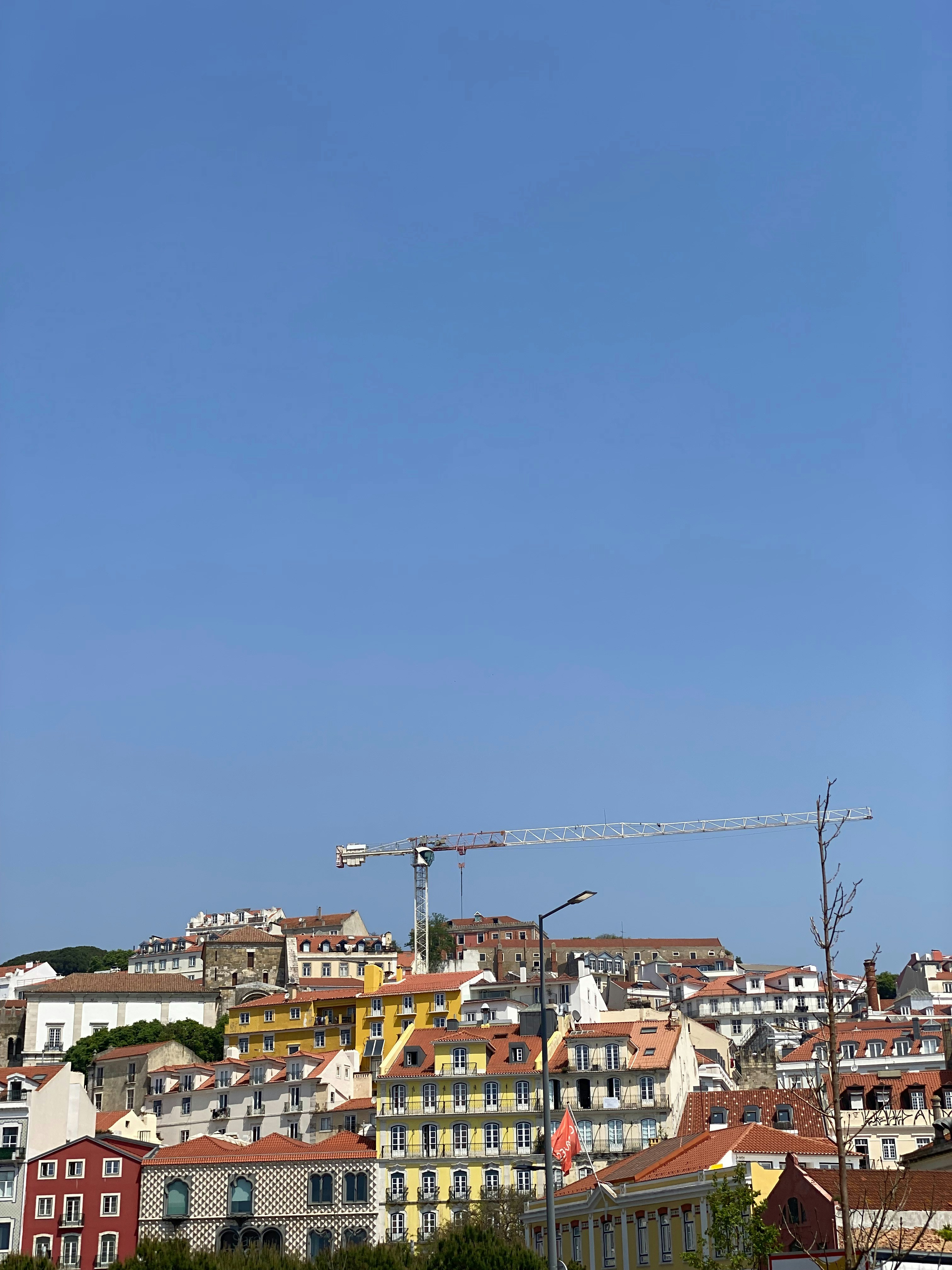 Crane Over a Patchwork Roofscape Beneath a Cerulean Sky