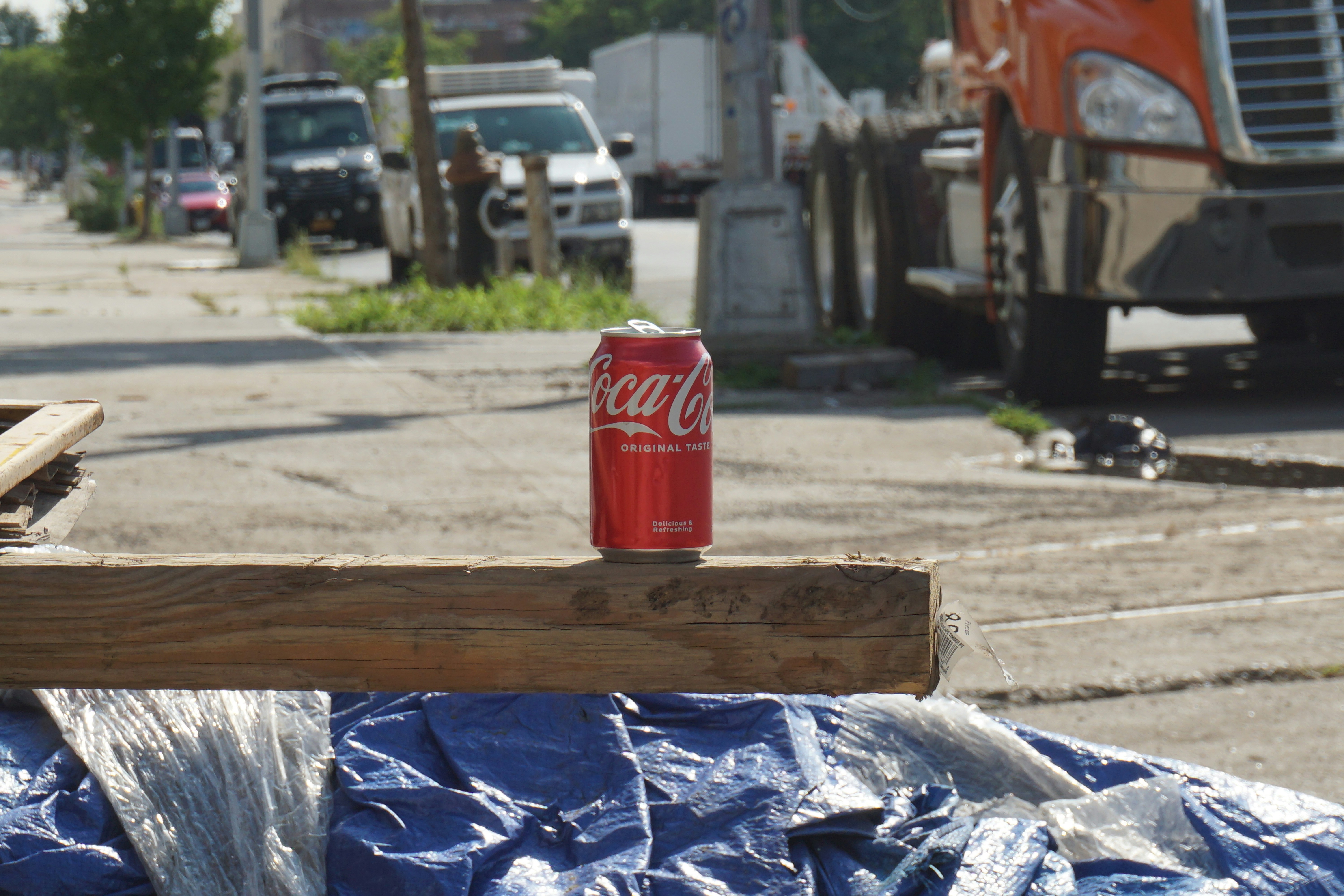 Midday Coke Standout: A Red Can on a Weathered Beam
