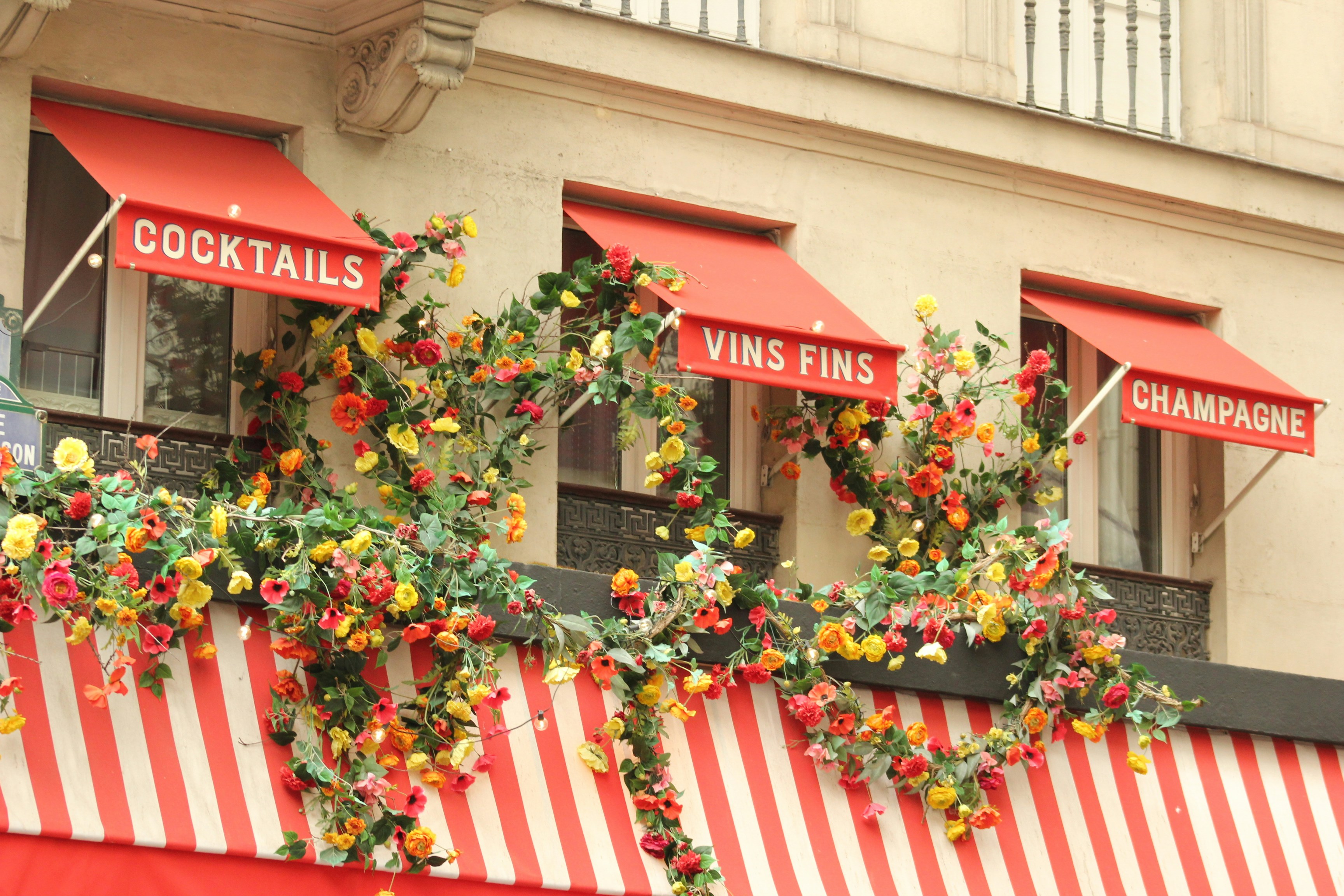Bouquet Arches Over a Red-Striped Parisian Café Awning