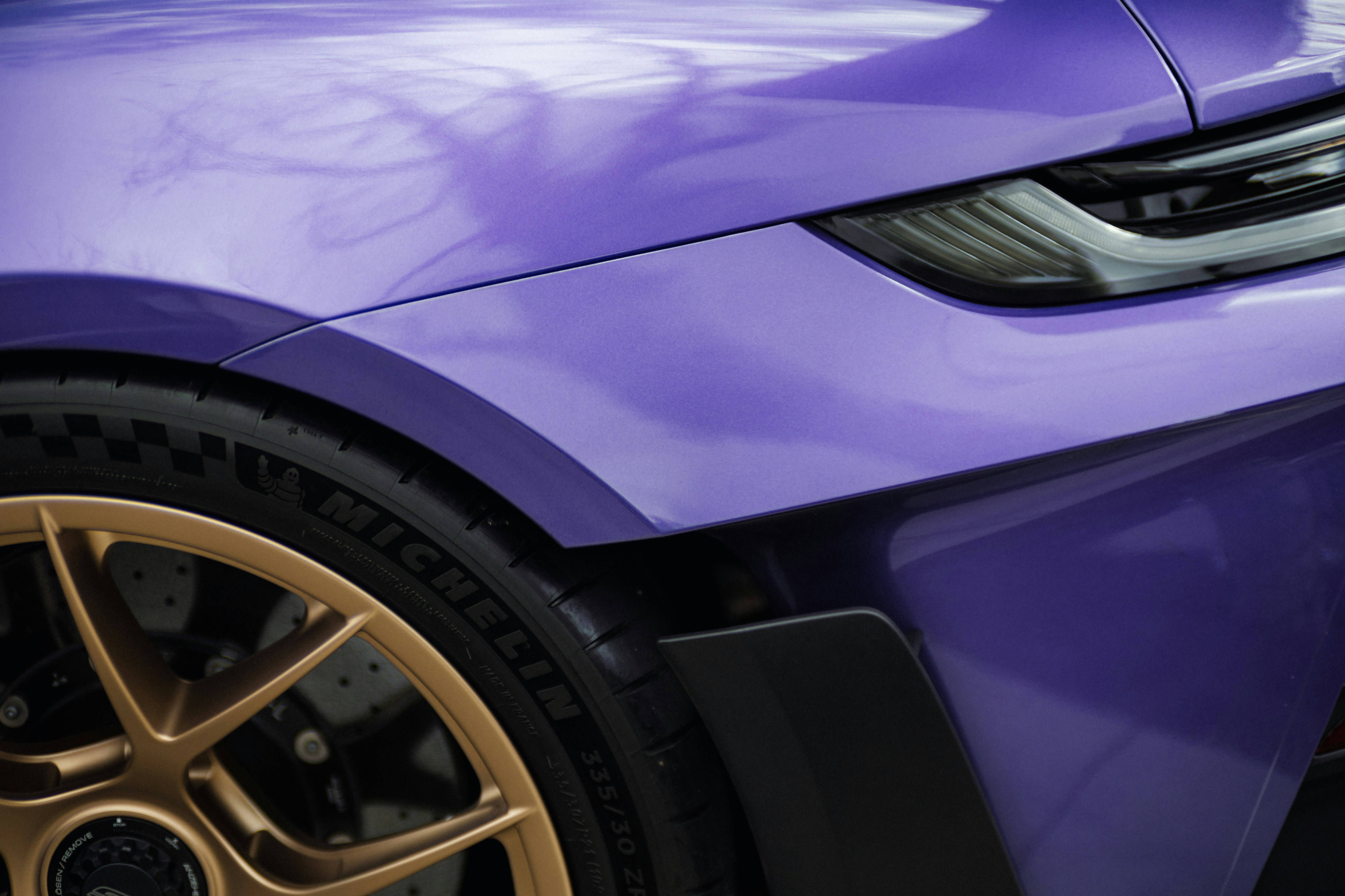 Gilded Spokes Under Violet Curves: A Close-Up Portrait of a Sports Car