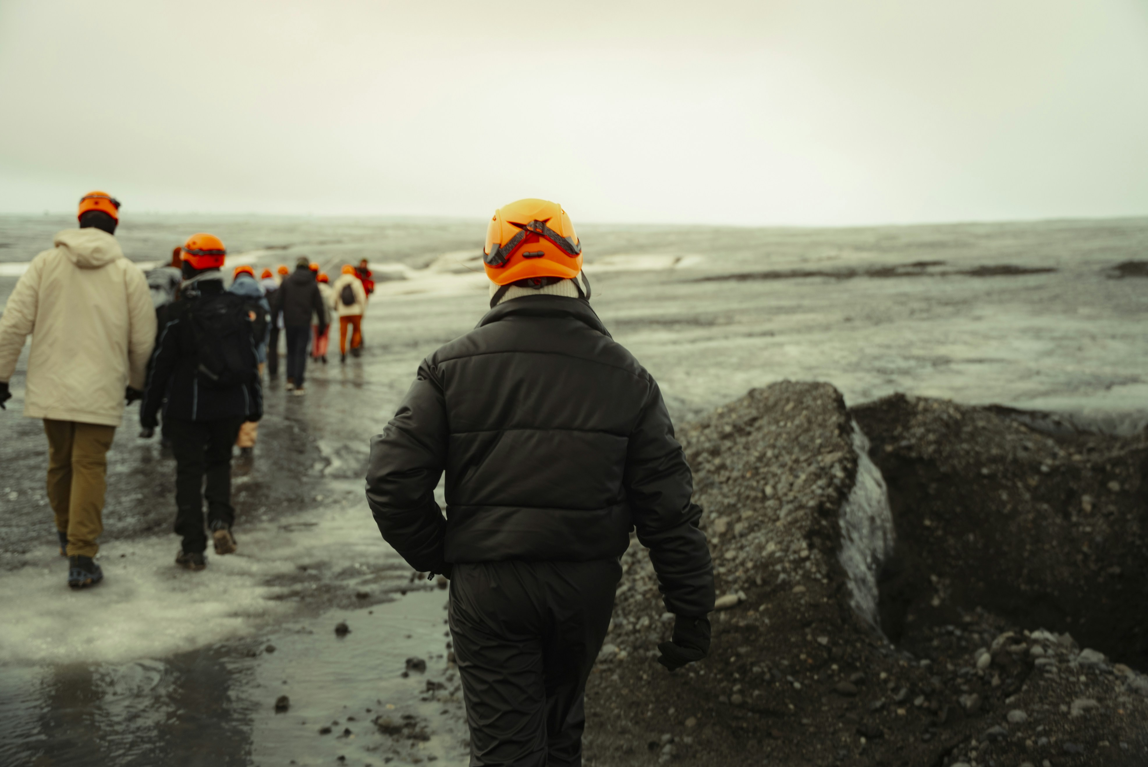 March of the Orange Helmets Across a Volcanic Shore