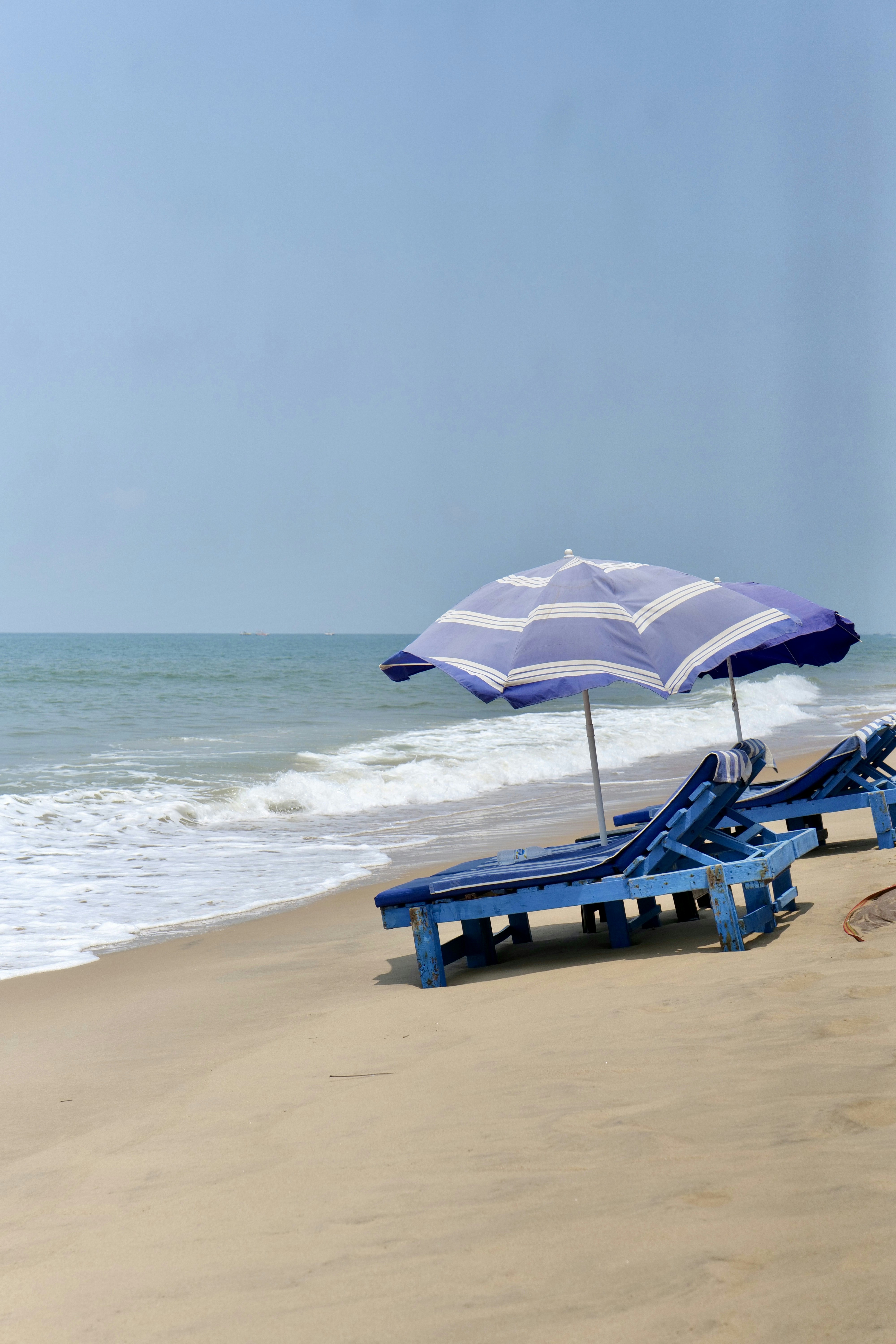 A couple of blue lounge chairs sitting on top of a sandy beach photo ...