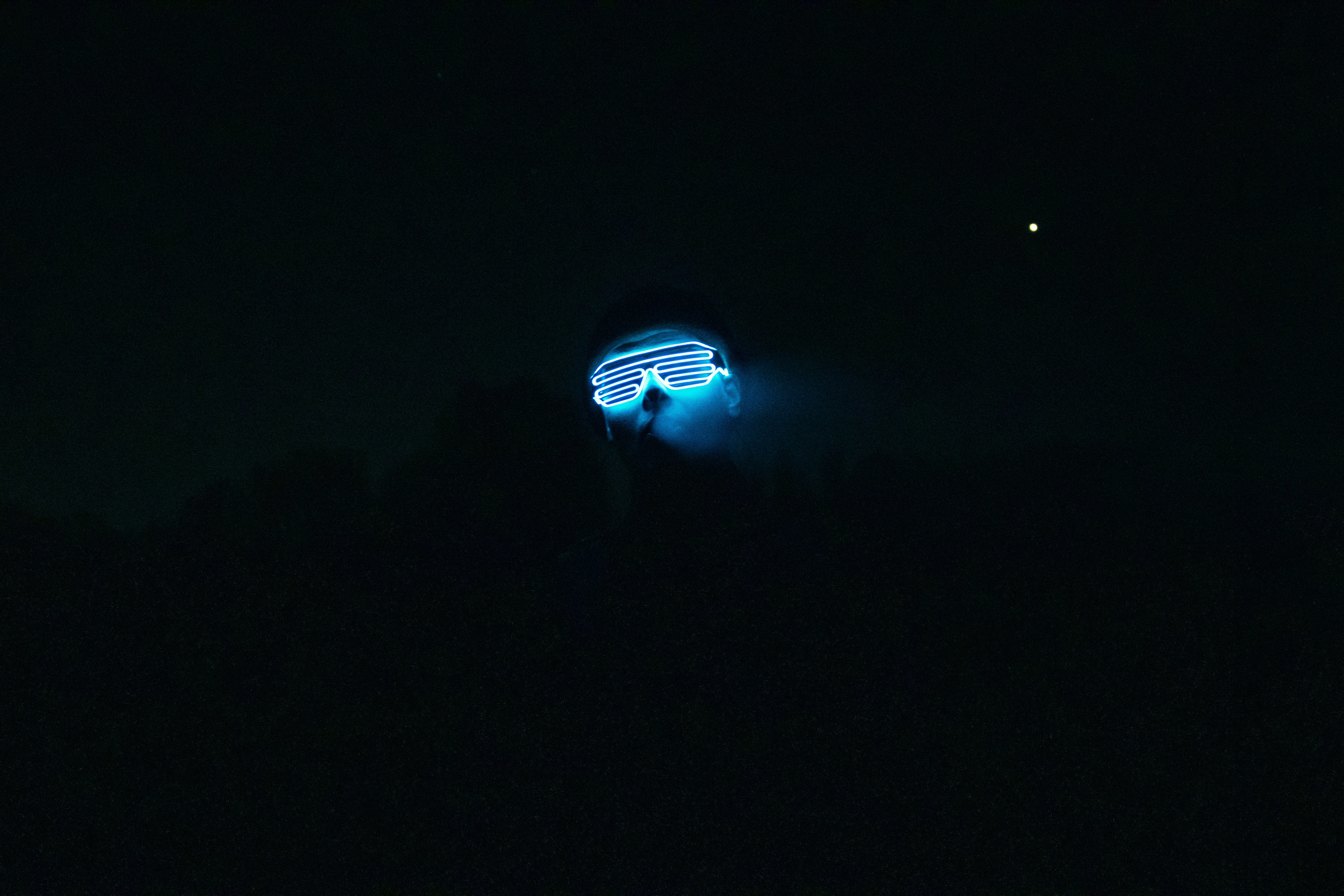 Faint blue light hovering in a dark night sky with a distant star visible.