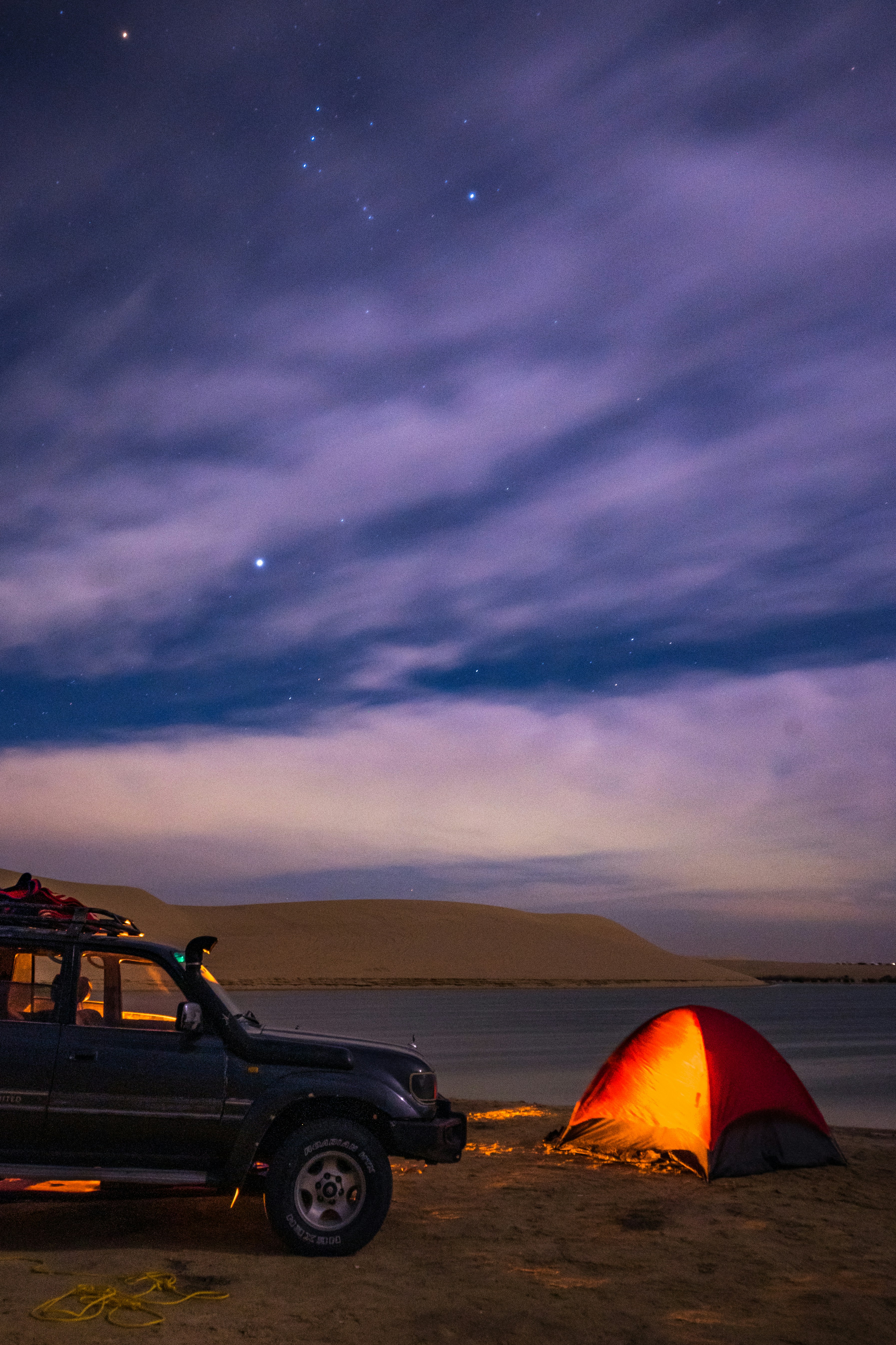 Horizon Camplight: An Orange Tent Amid a Quiet Desert Night Under Stars