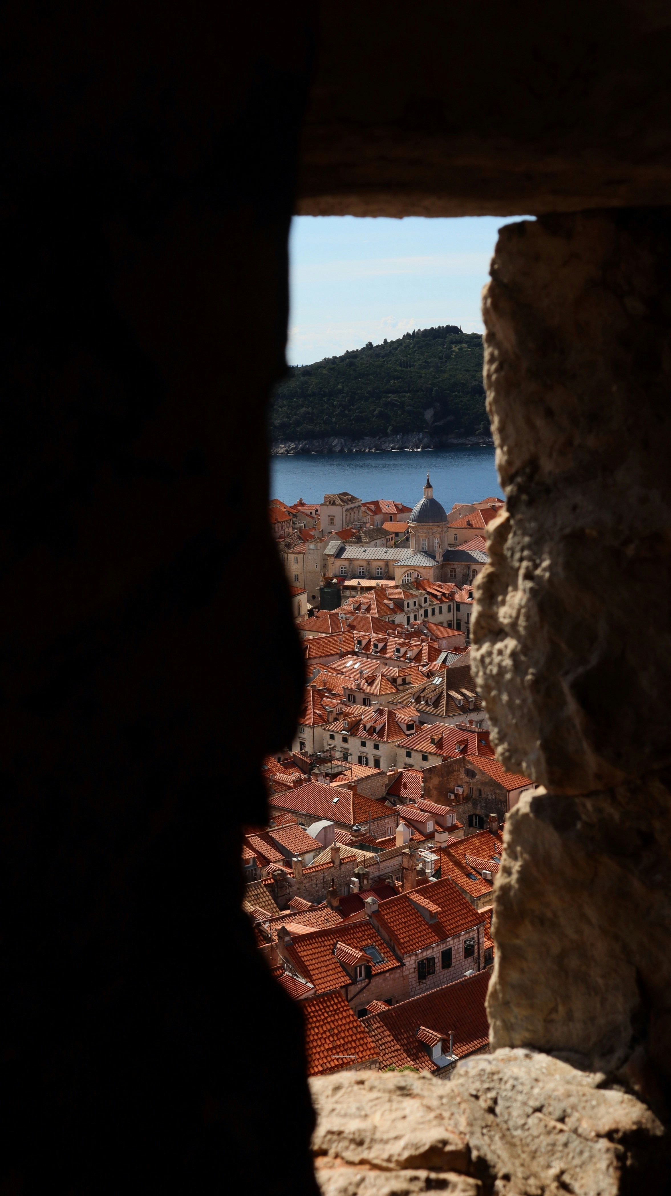 A view of a city through a hole in a stone wall photo – Free Old town ...