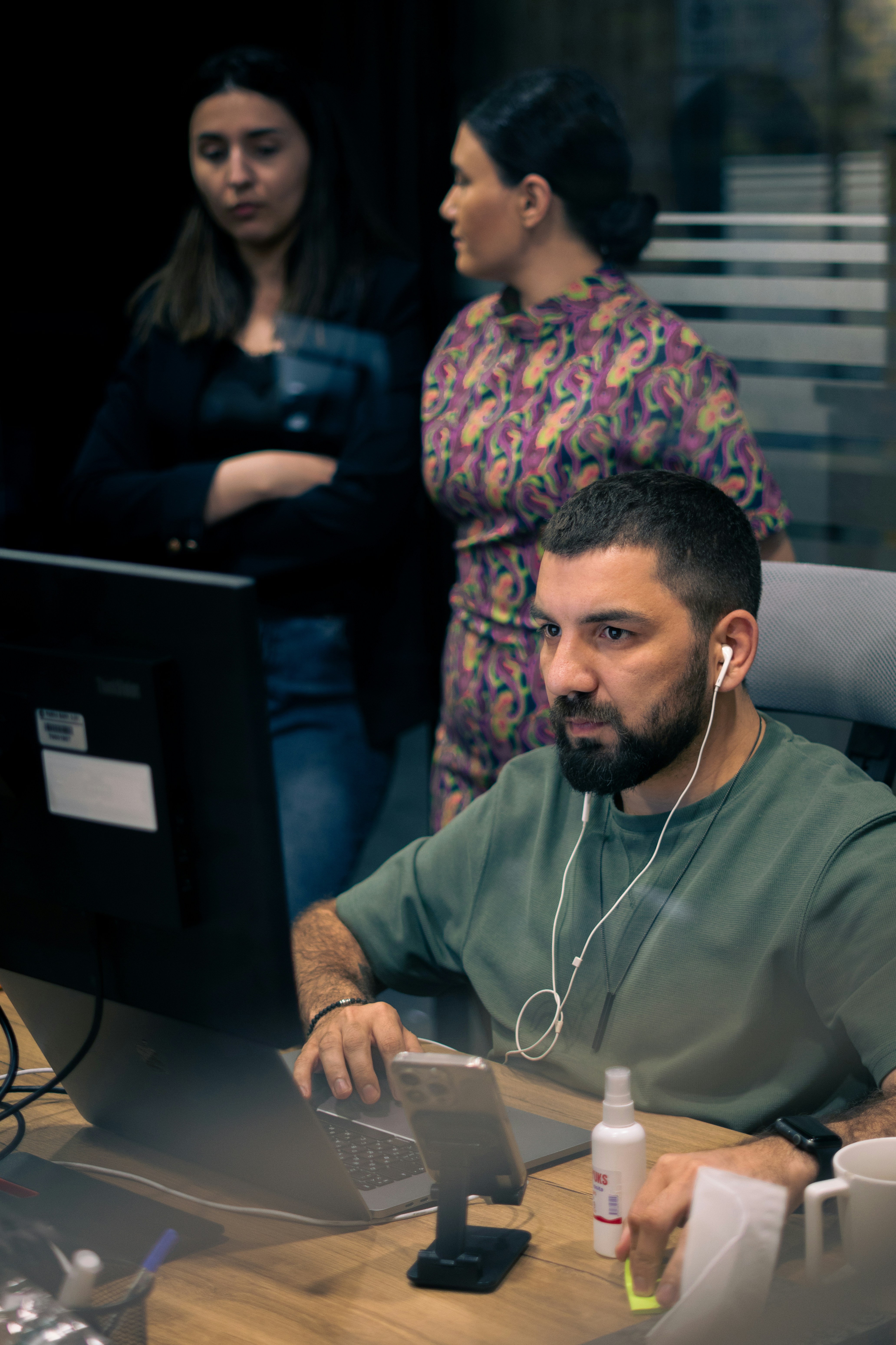 Focused at the Screen: A coder in the foreground with two colleagues in the background