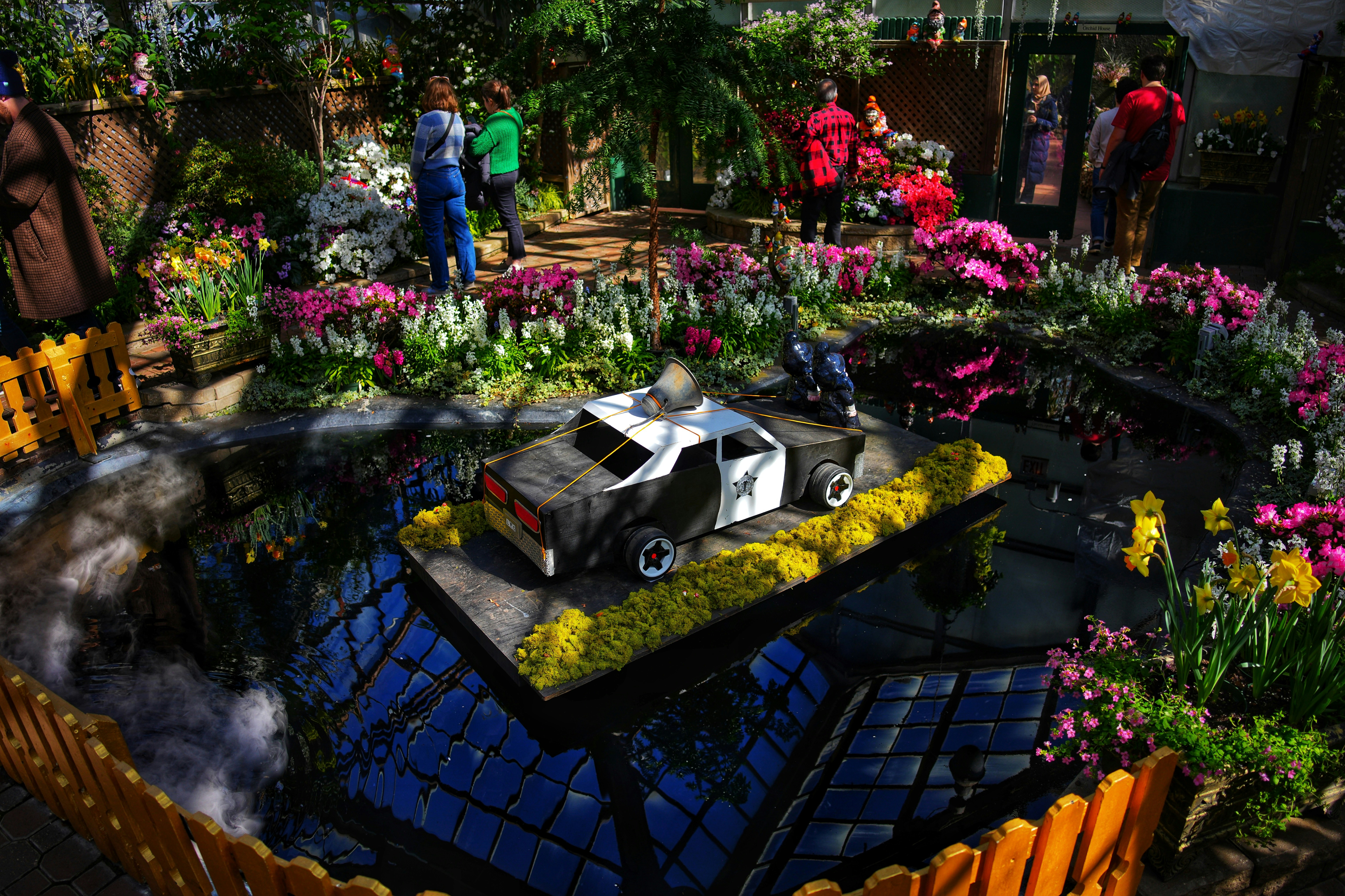 Miniature River Run: The Glass-Deck Parade Car Circles a Floral Oasis