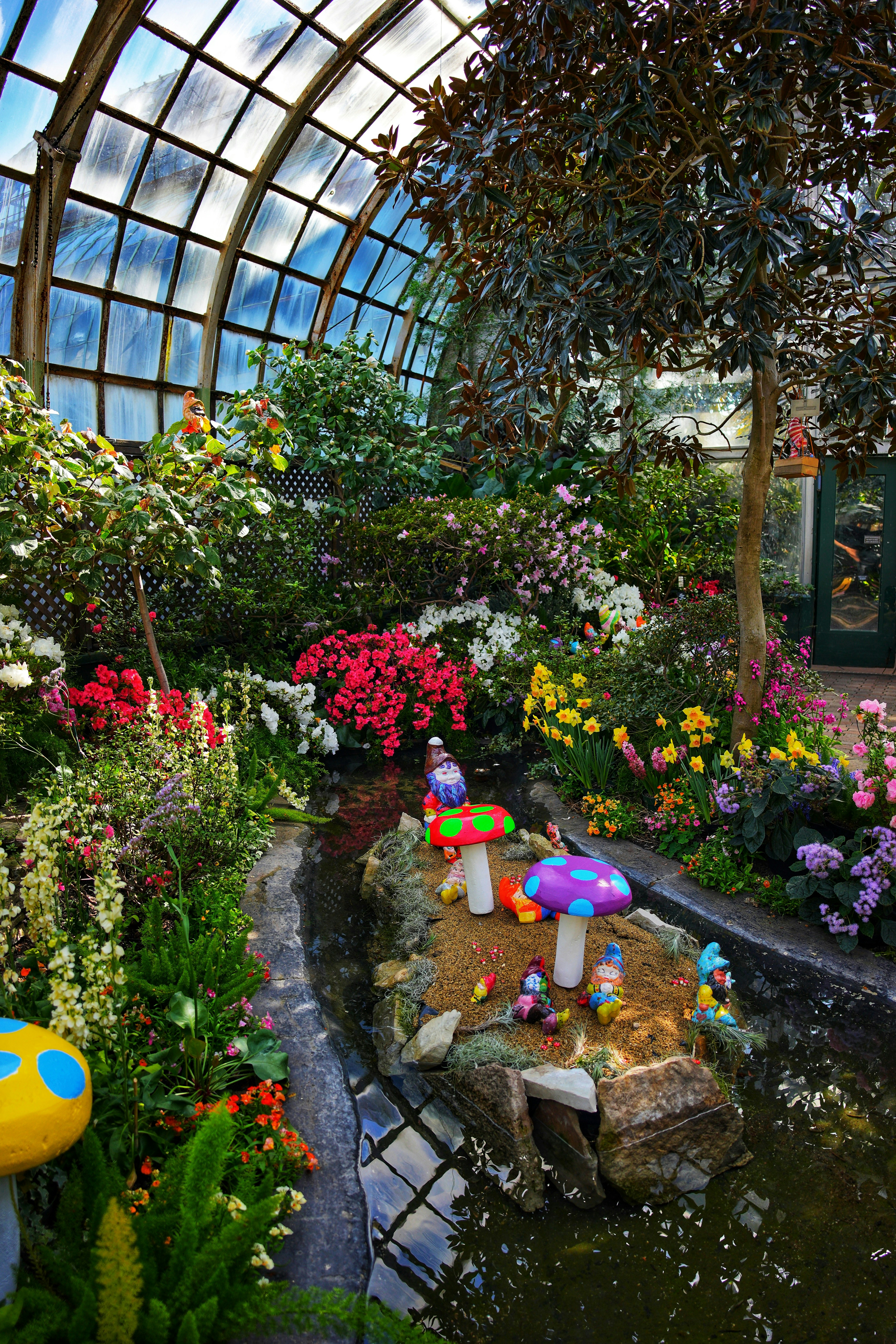 Verdant Conservatory Cascade: Colorful Garden Ornaments Amid Glass Roof
