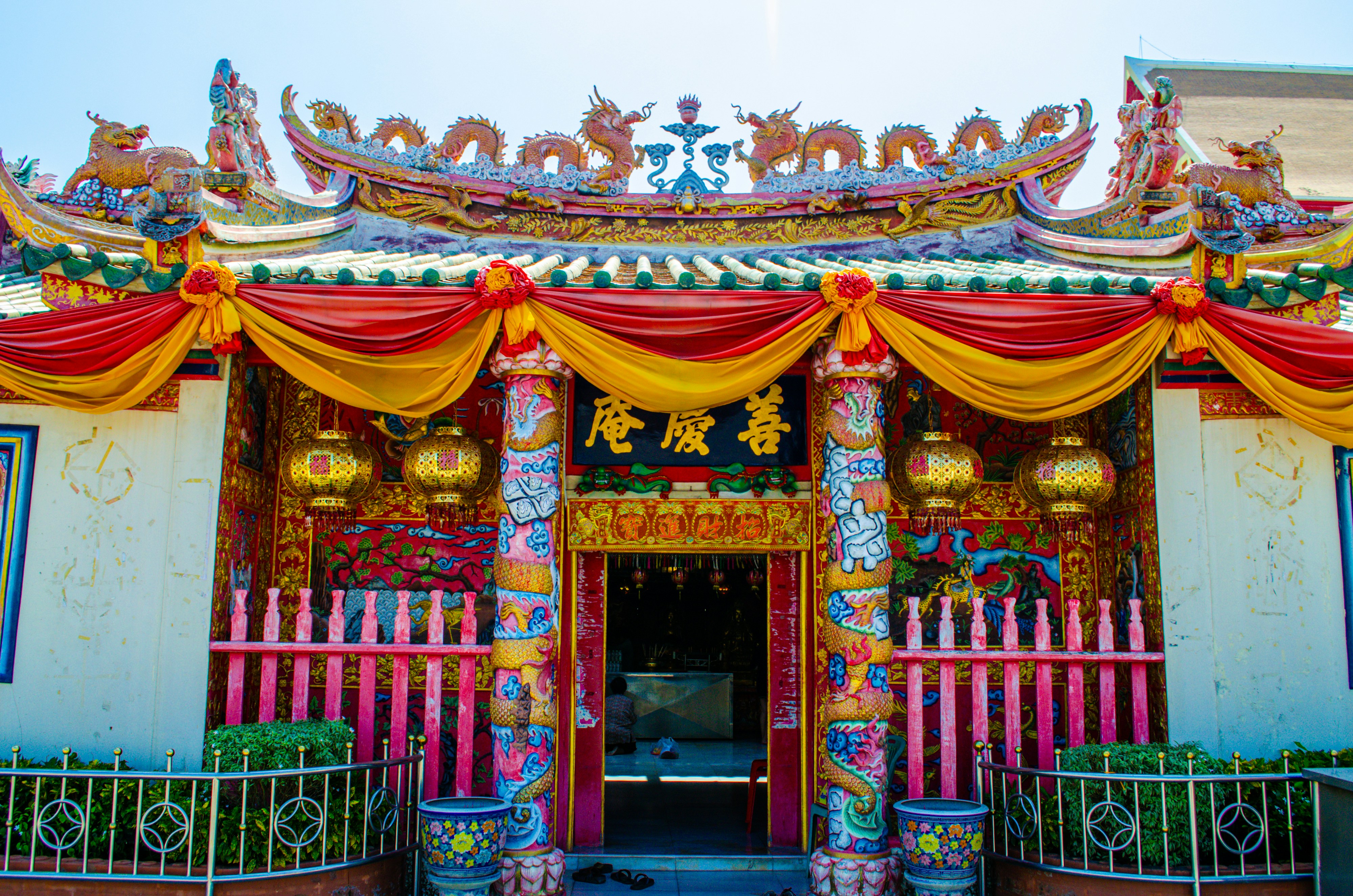 Intricately decorated temple entrance adorned with colorful dragons and lanterns, showcasing cultural artistry and devotion.