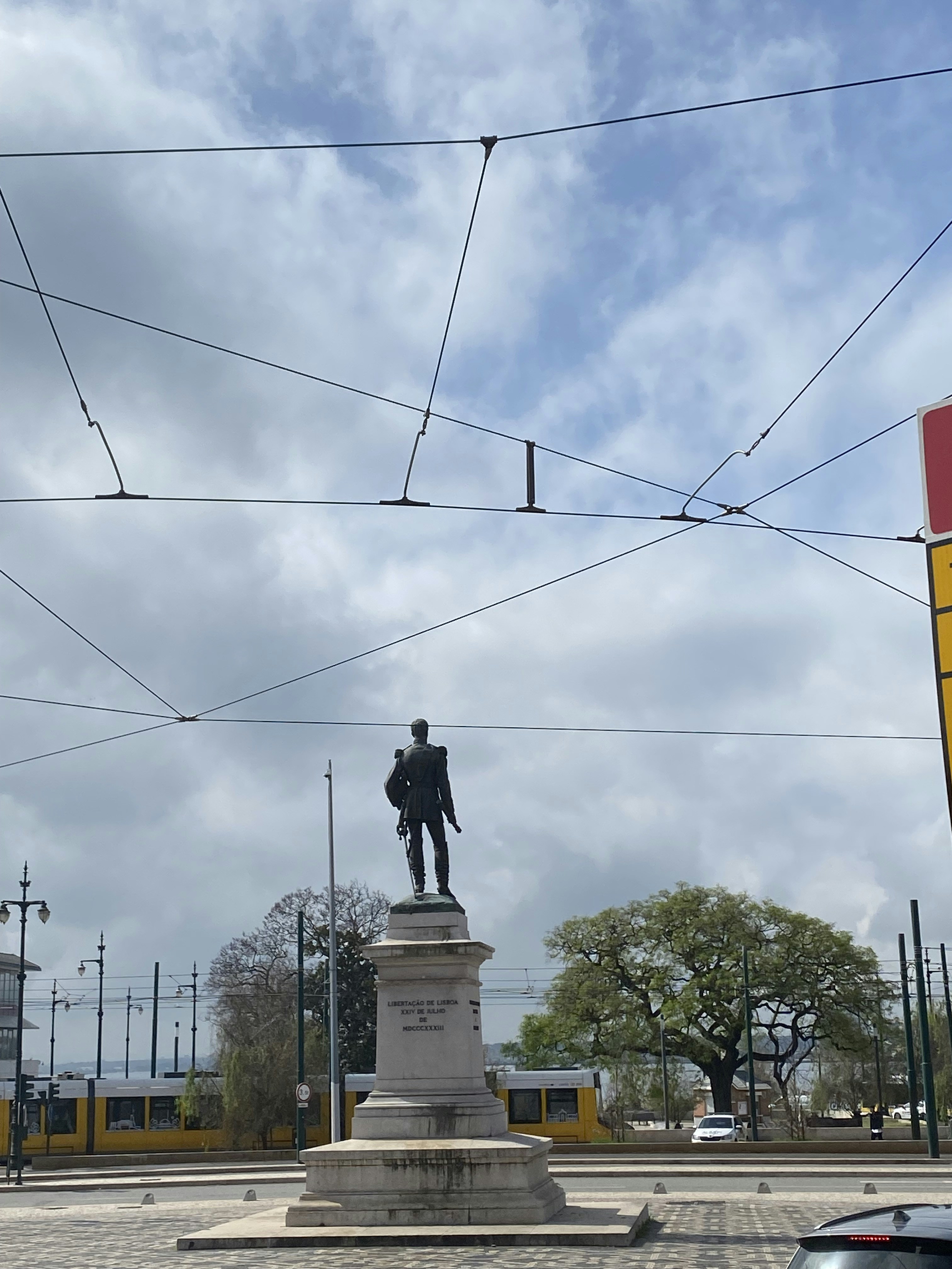 Statue in a City Spiderweb: A Monumental Figure Against Urban Tram Lines