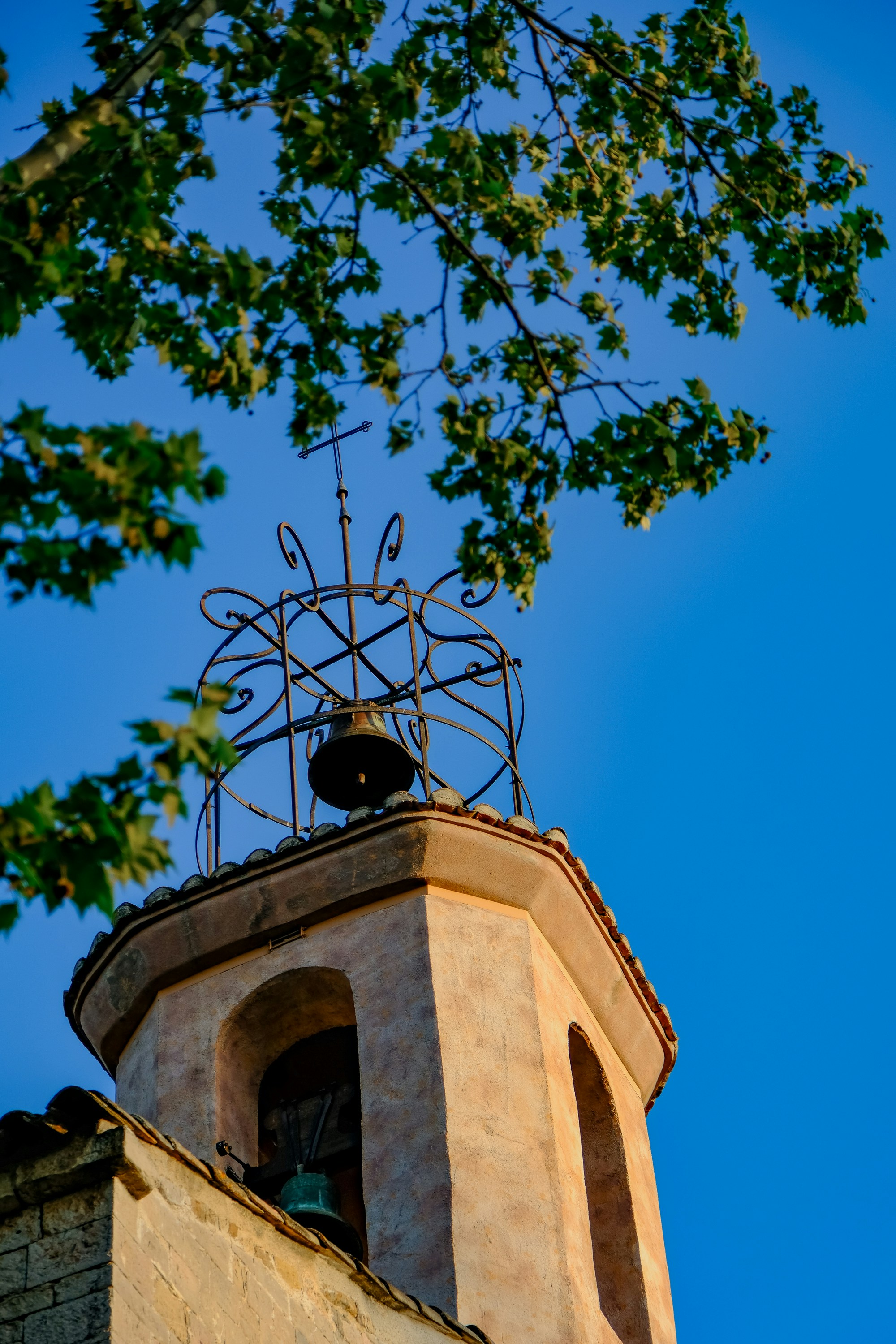 Iron Lattice Crown Tops a Sunlit Bell Tower Against a Cobalt Sky