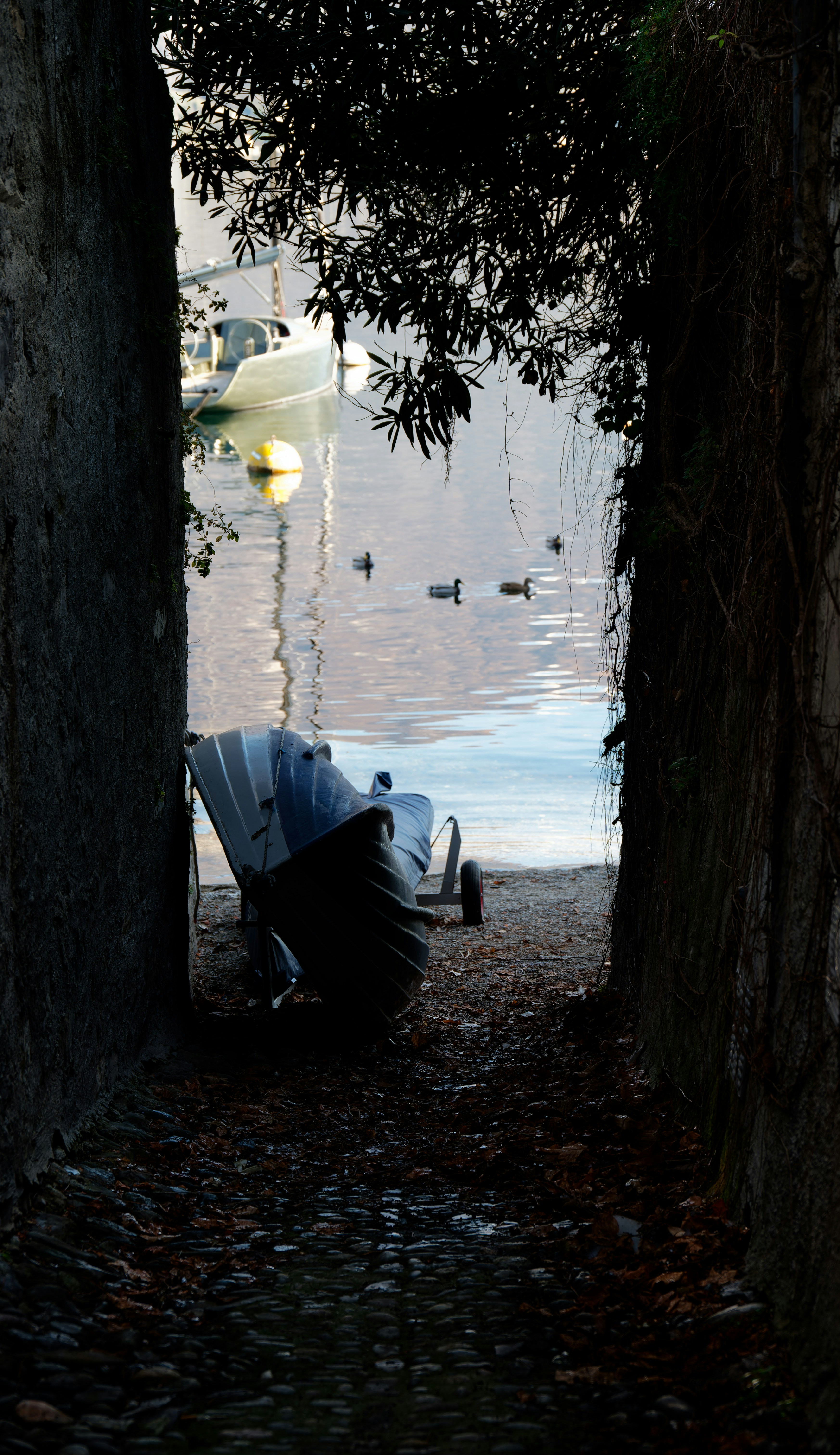 Boat silhouette framed by a shadowed tunnel to a sunny harbor