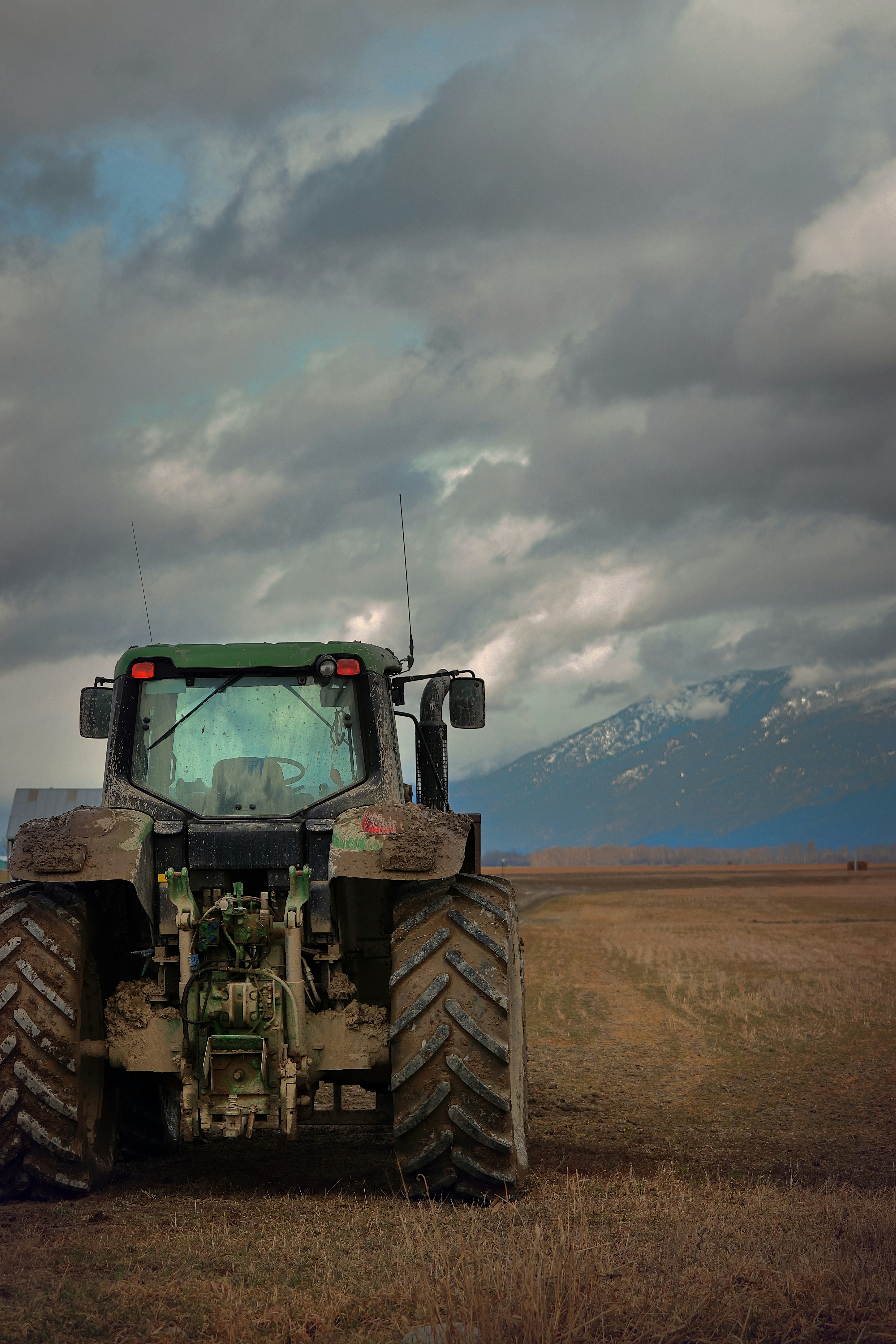 A tractor is parked in a field with mountains in the background photo ...
