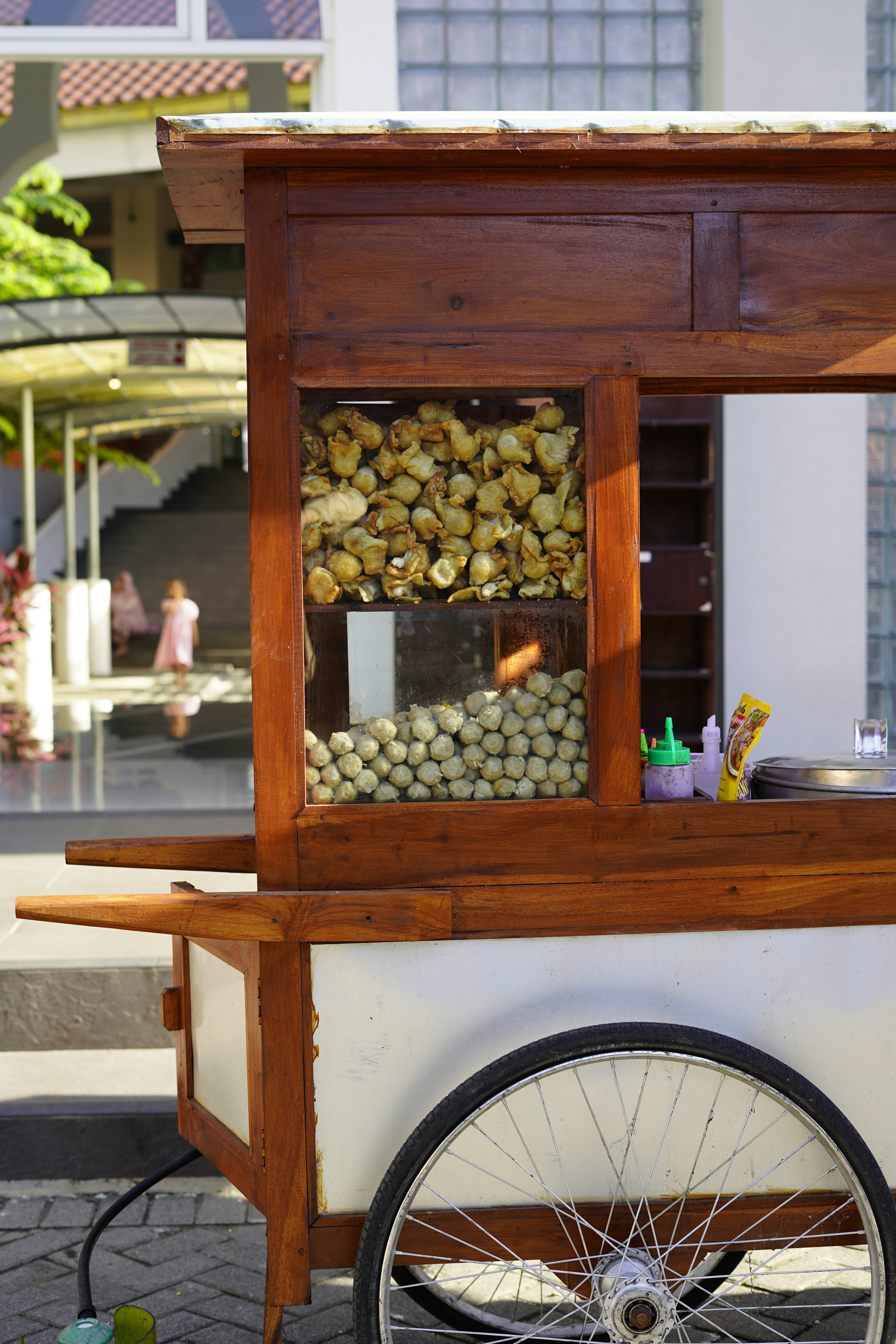 A vibrant street food cart showcasing an array of traditional snacks, with a wooden structure and a clear display of colorful treats. The bustling atmosphere adds to its charm.