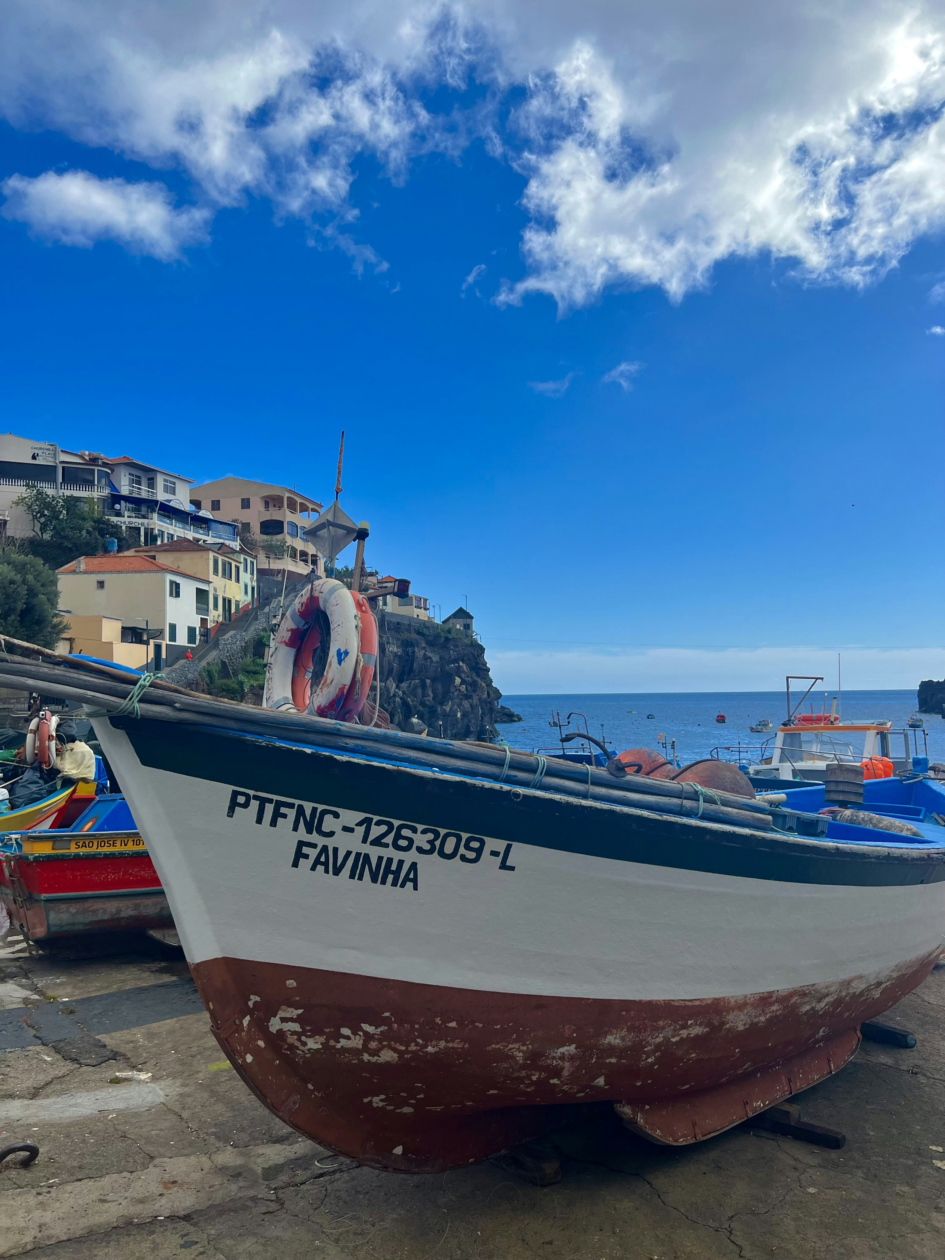 Quayfront Vessel: A White-Hulled Boat Anchored as Colorful Dwellings Rise the Cliffside