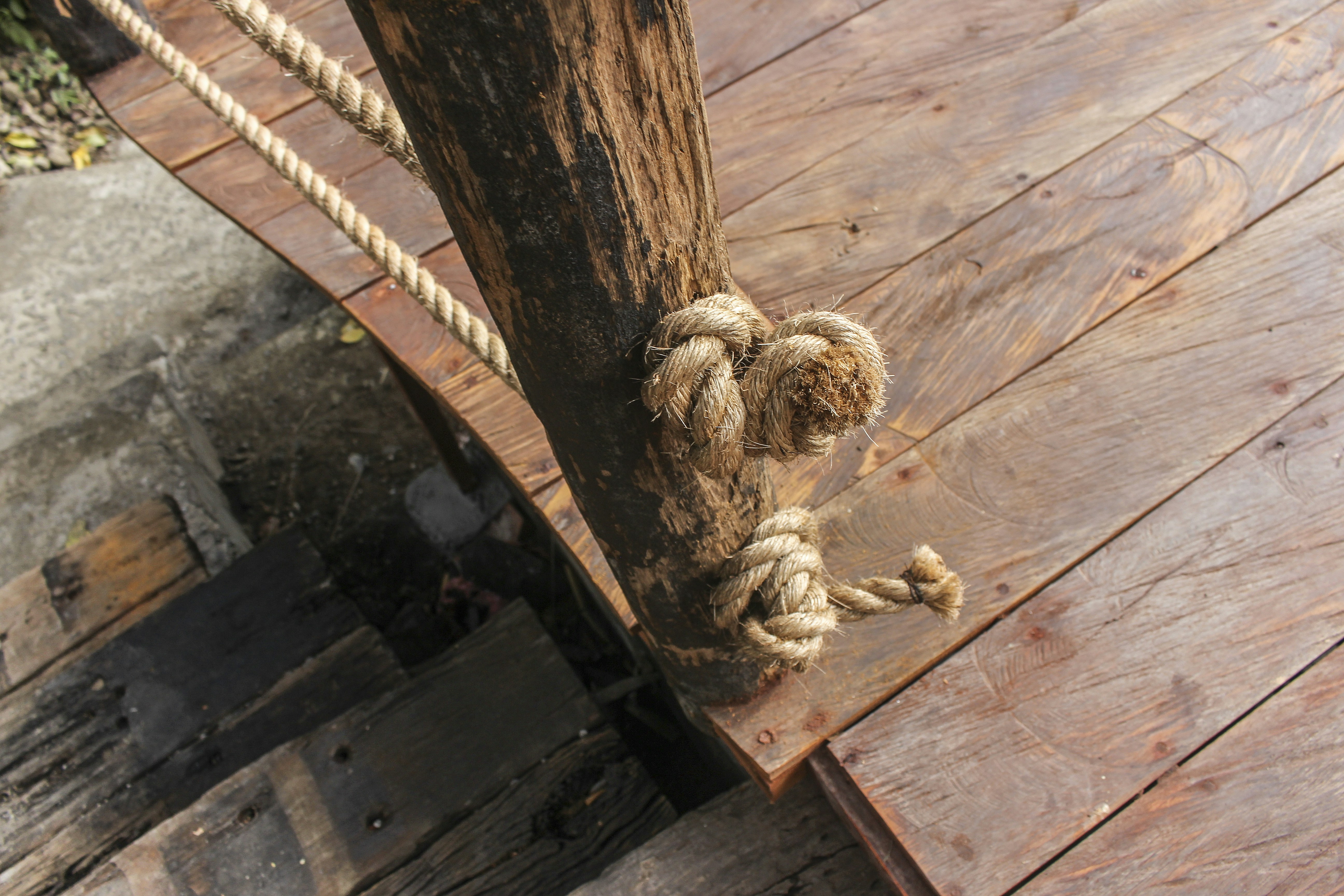Frayed rope knot gripping a weathered post on a sun-warmed deck
