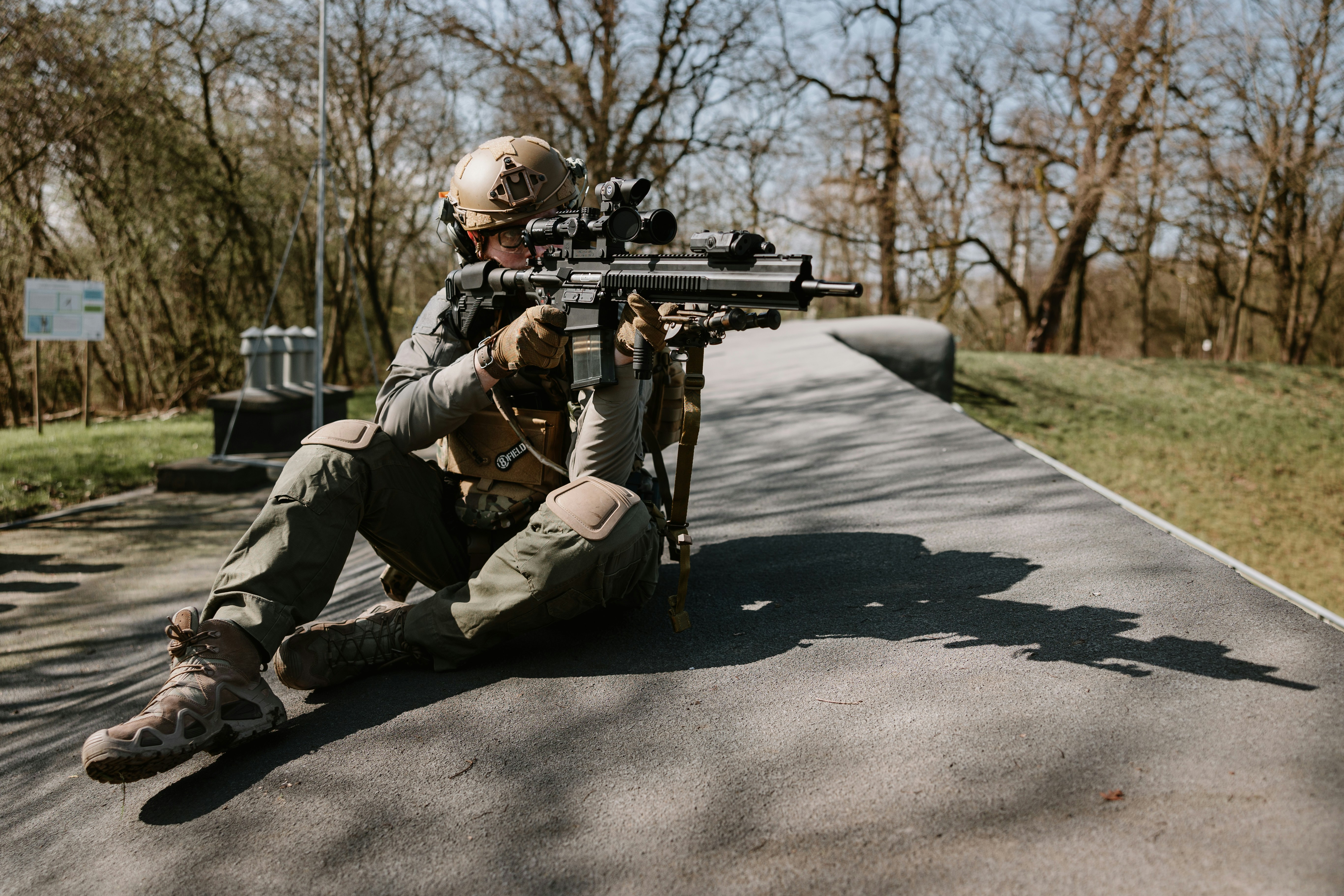 A man with a rifle sitting on the ground photo – Free Tactical gear ...