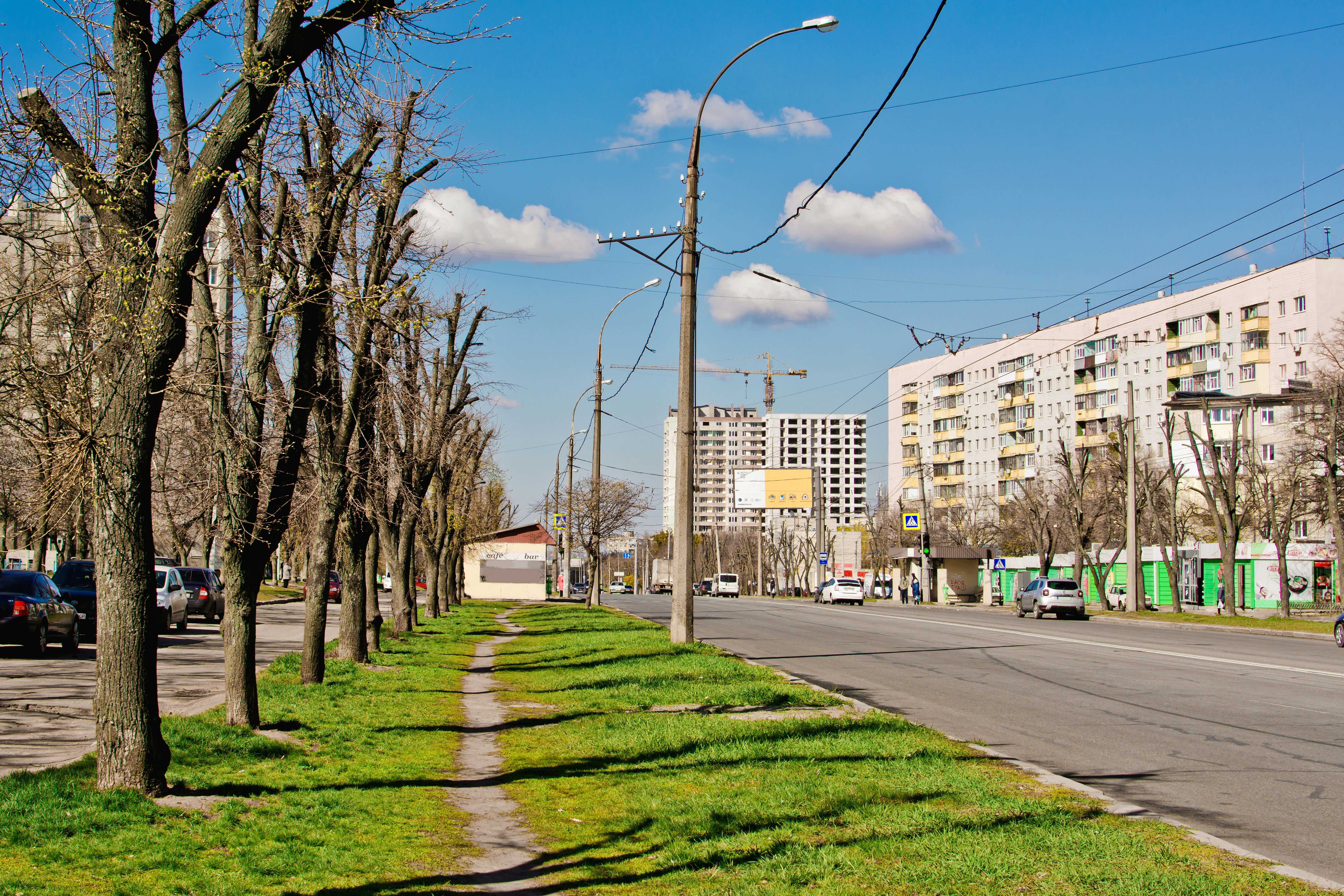 traffic on a city street on a sunny day against a blue cloudy sky and houses