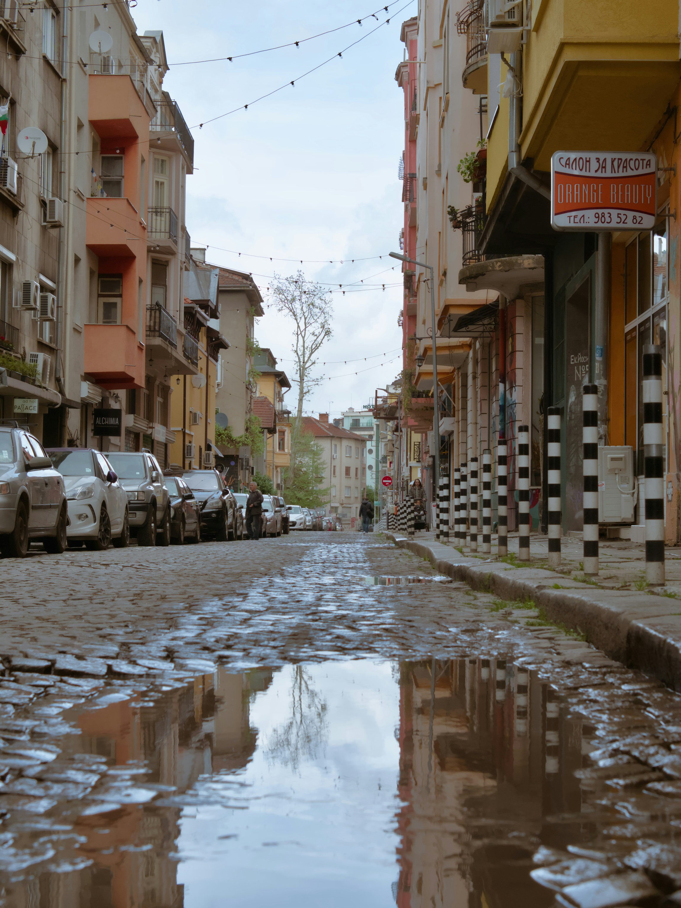 Rain-Kissed Cobblestones: A Quiet Street Framed by Balconies and String Lights