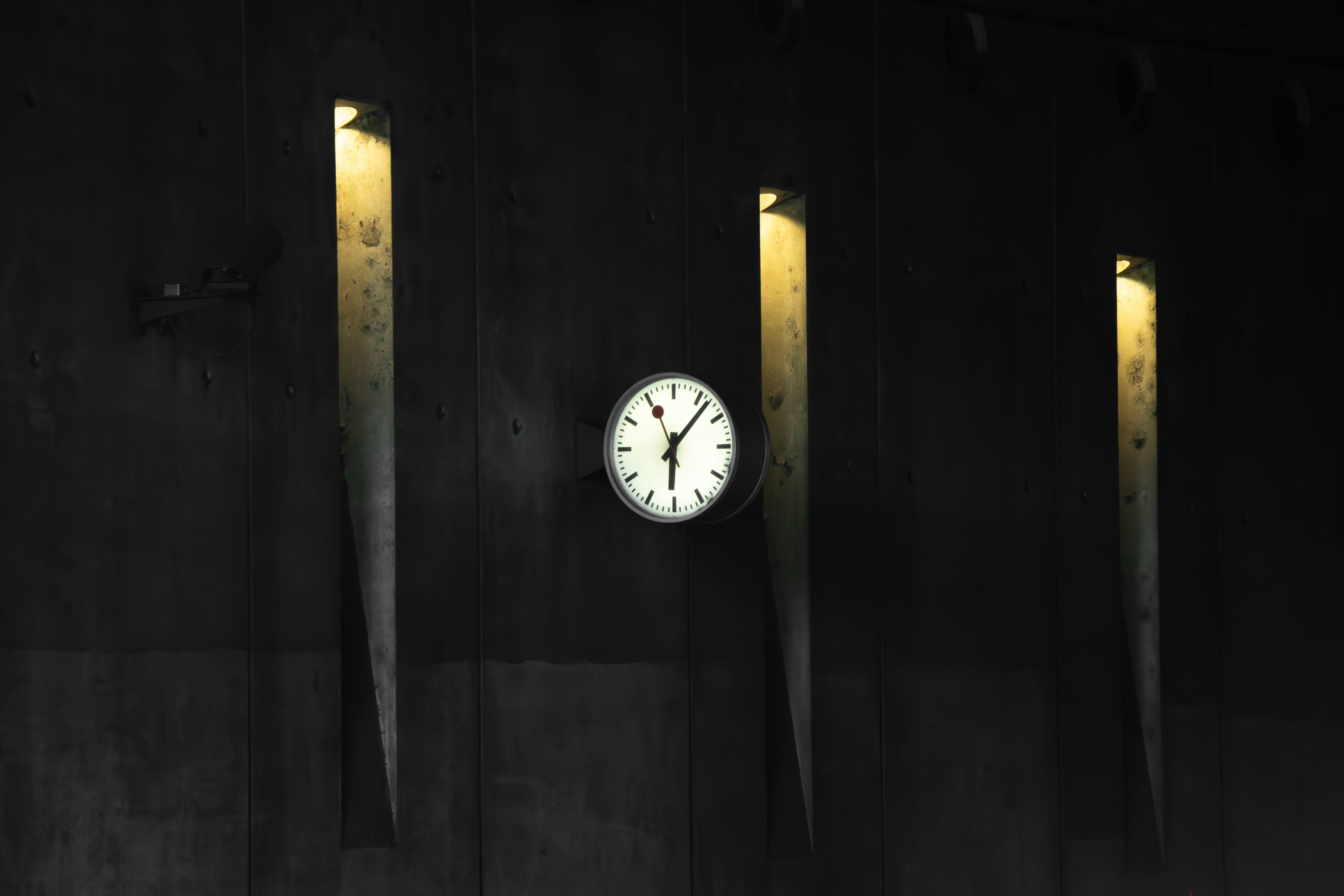 Clock Between Light Strips: Time Pauses in a Quiet Concrete Corridor