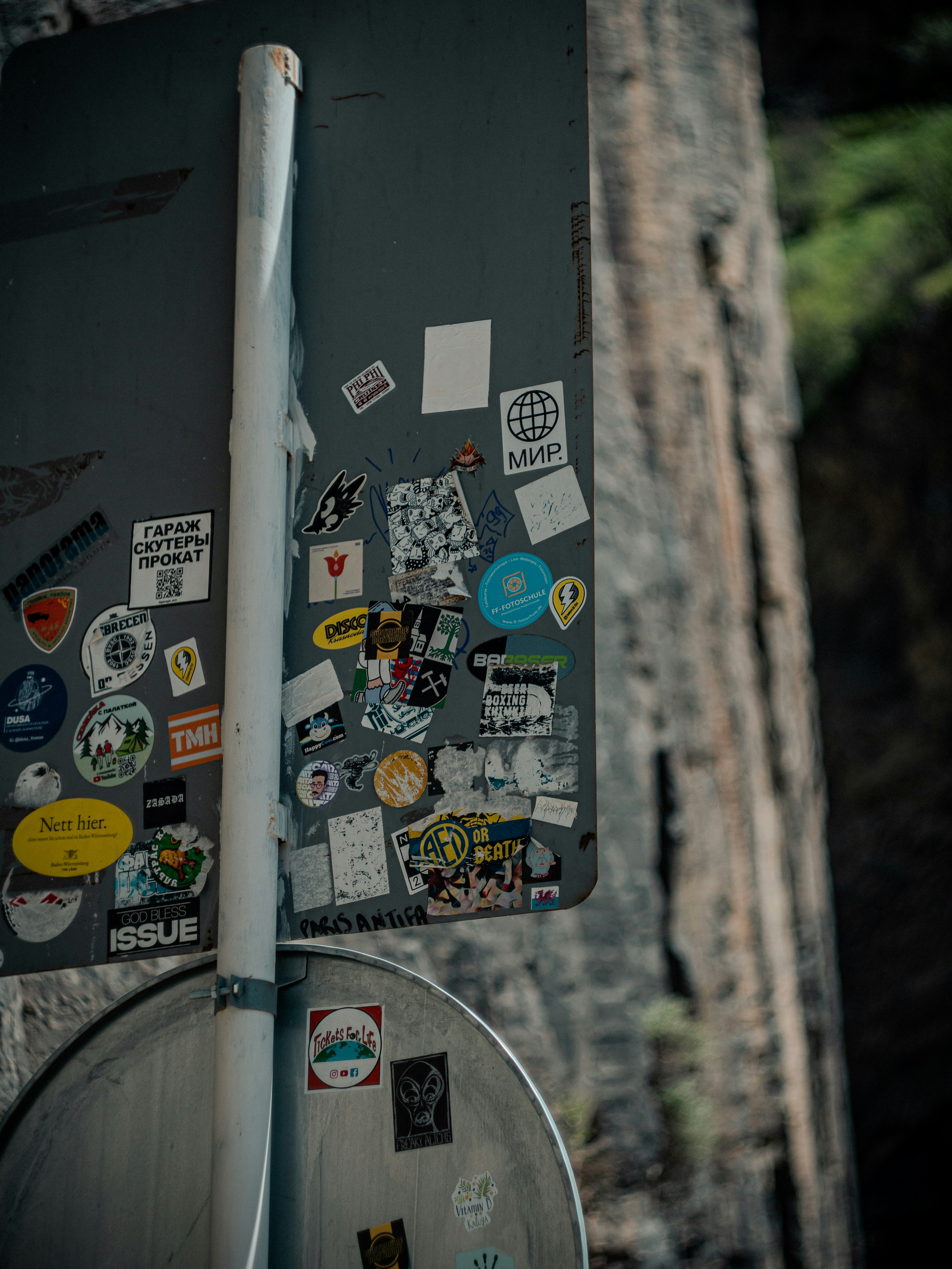 Stickered Post: A Vertical Gallery of Roadside Decals Clinging to a Weathered Sign