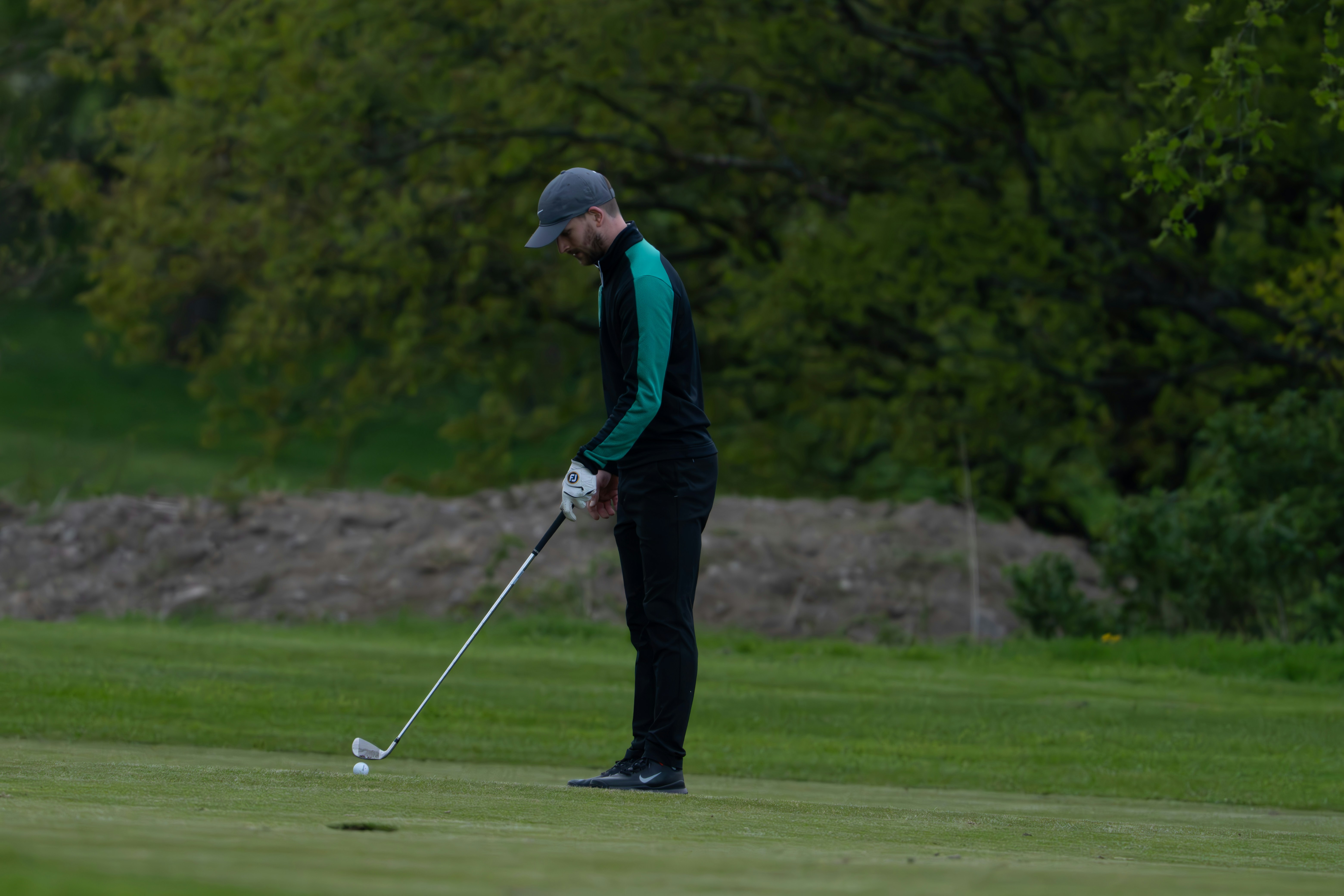 A golfer poised to take a swing on a lush green course, surrounded by vibrant trees. The scene captures the essence of concentration and skill.