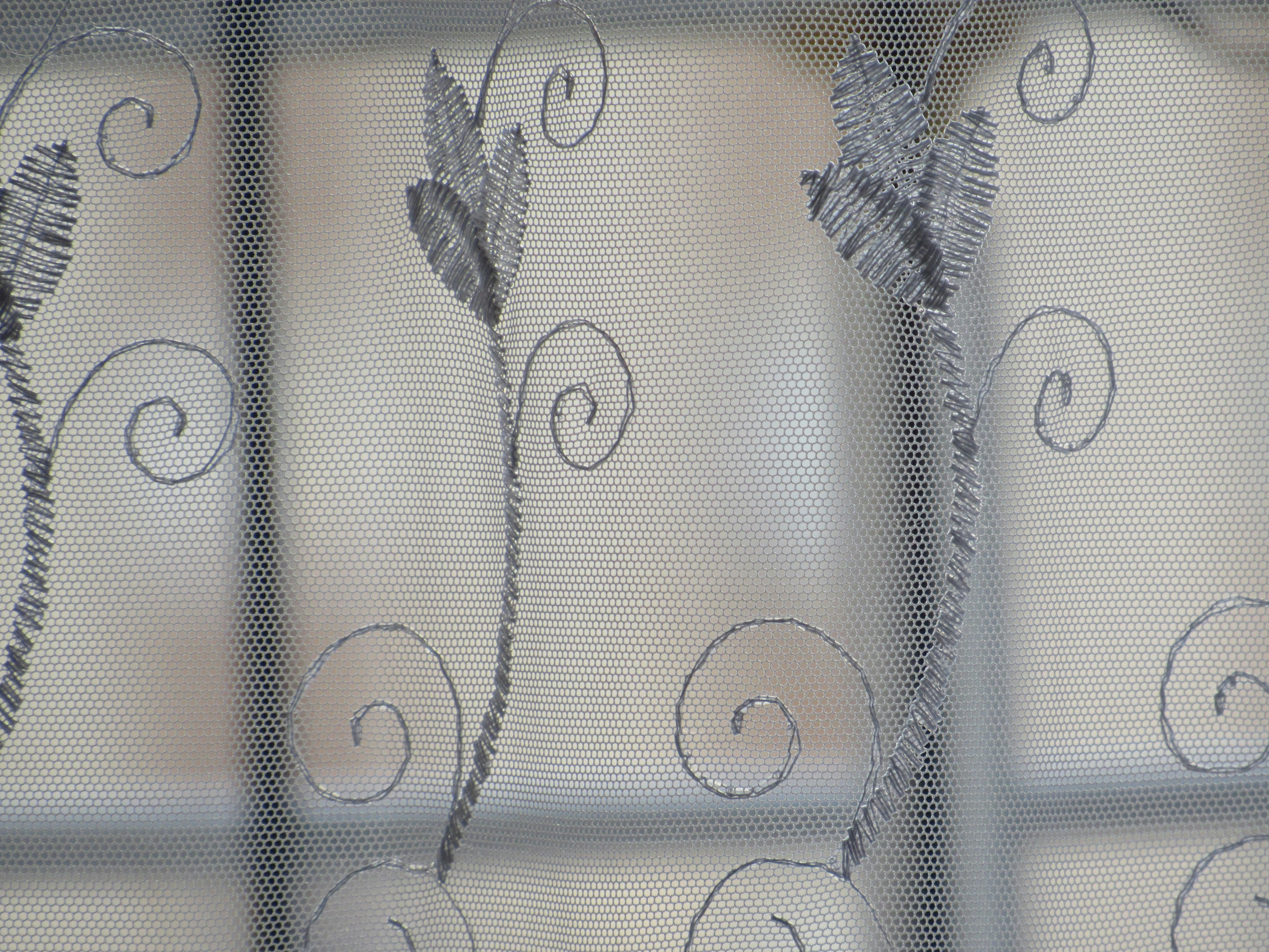 Macro of curling vine motifs on a translucent window grille