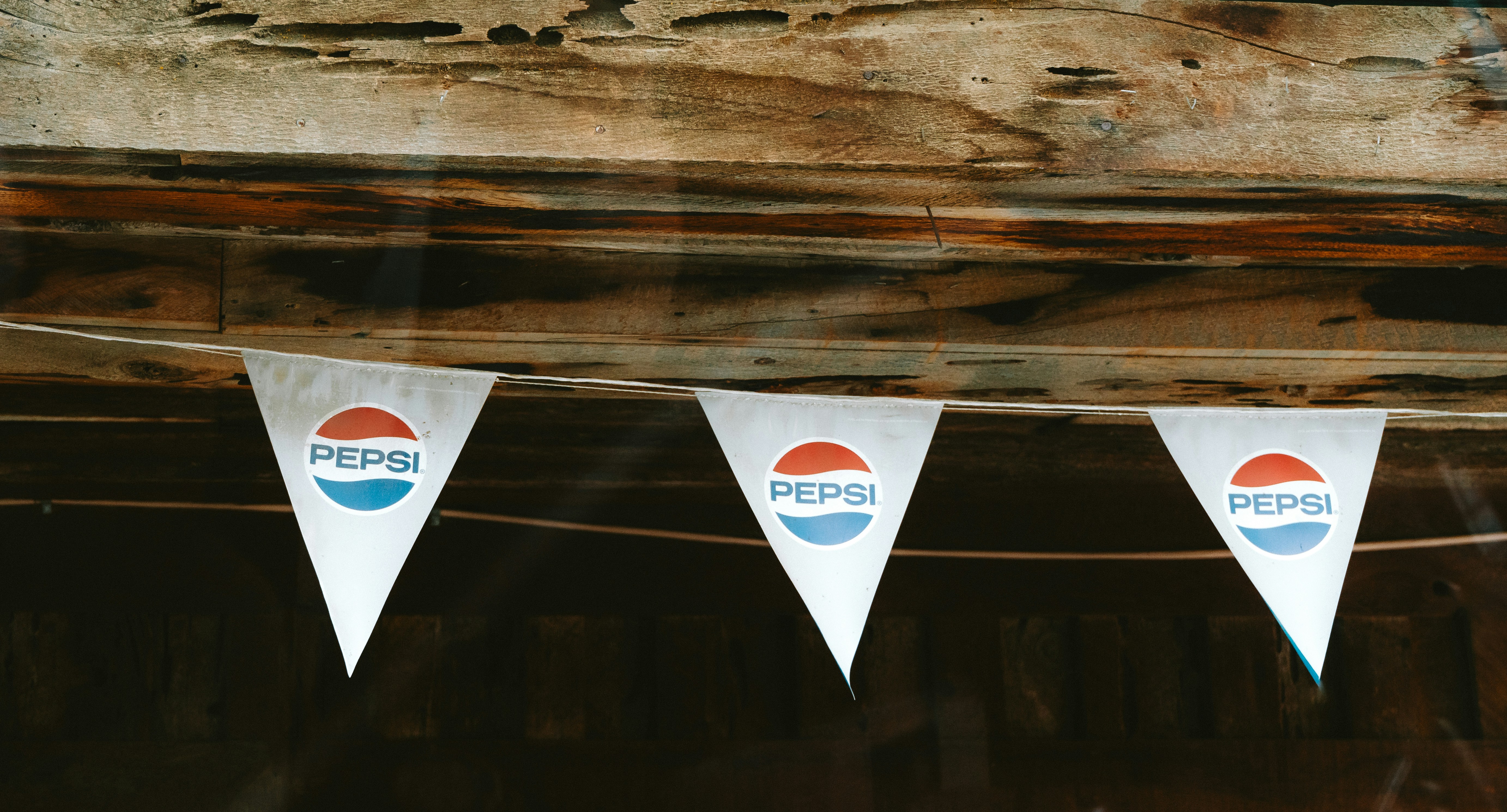 Three pepsi flags hanging from a line in front of a building photo ...