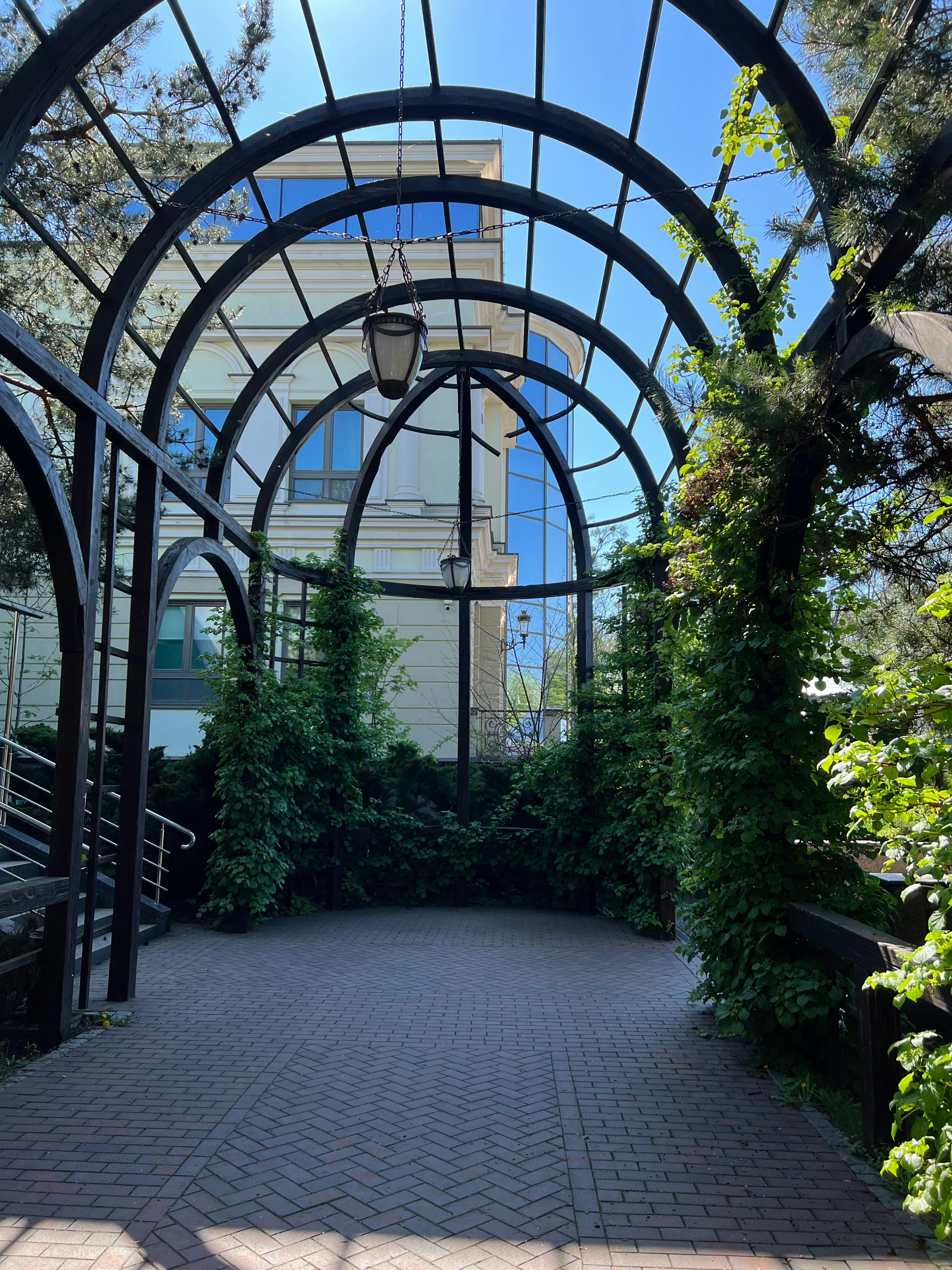 Arched walkway of shadow and light under a steel trellis
