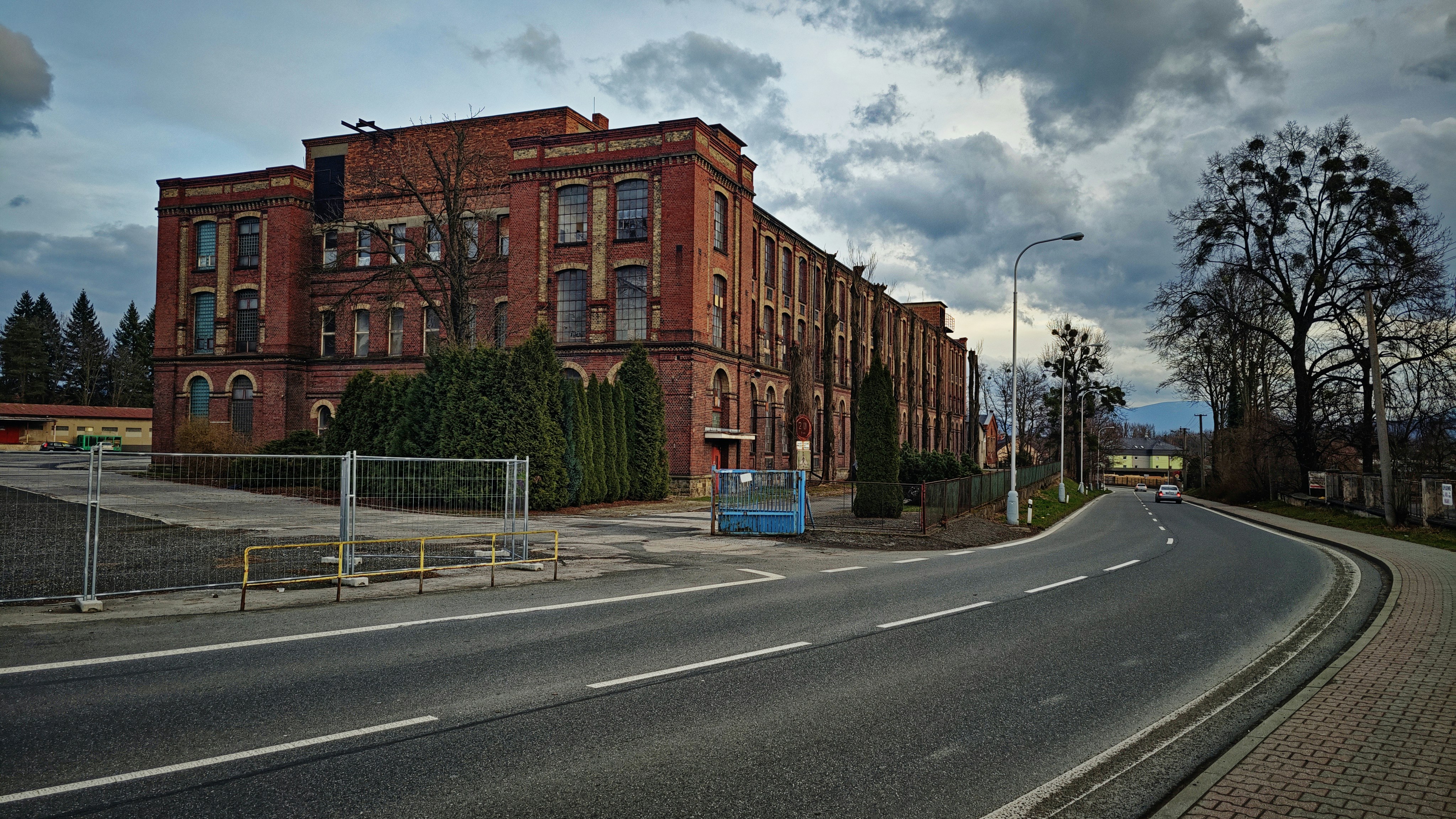 Red brick industrial building with intricate architecture under a cloudy sky.