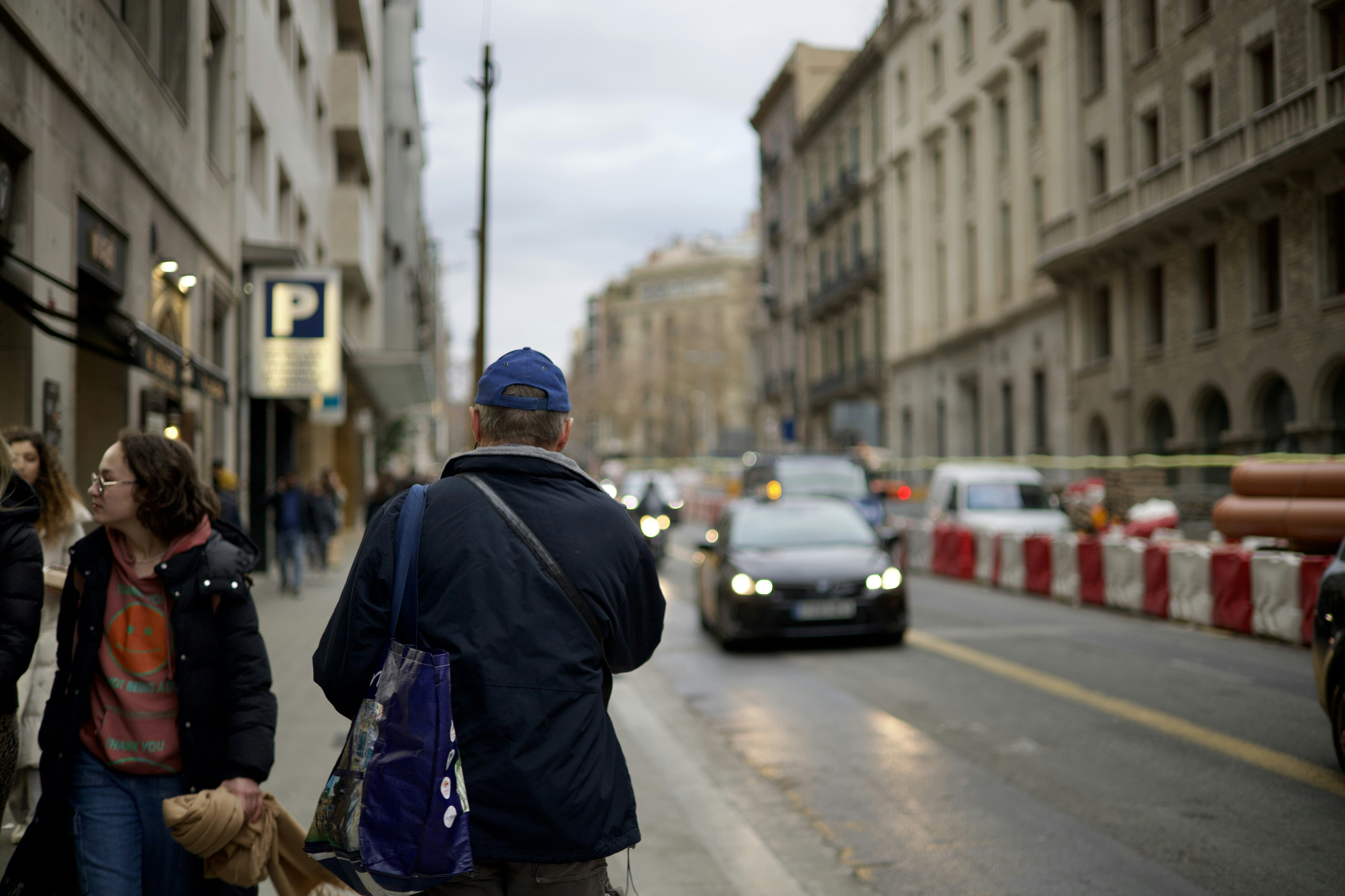 Back-turned Commuter on a City Street as Traffic Flows By