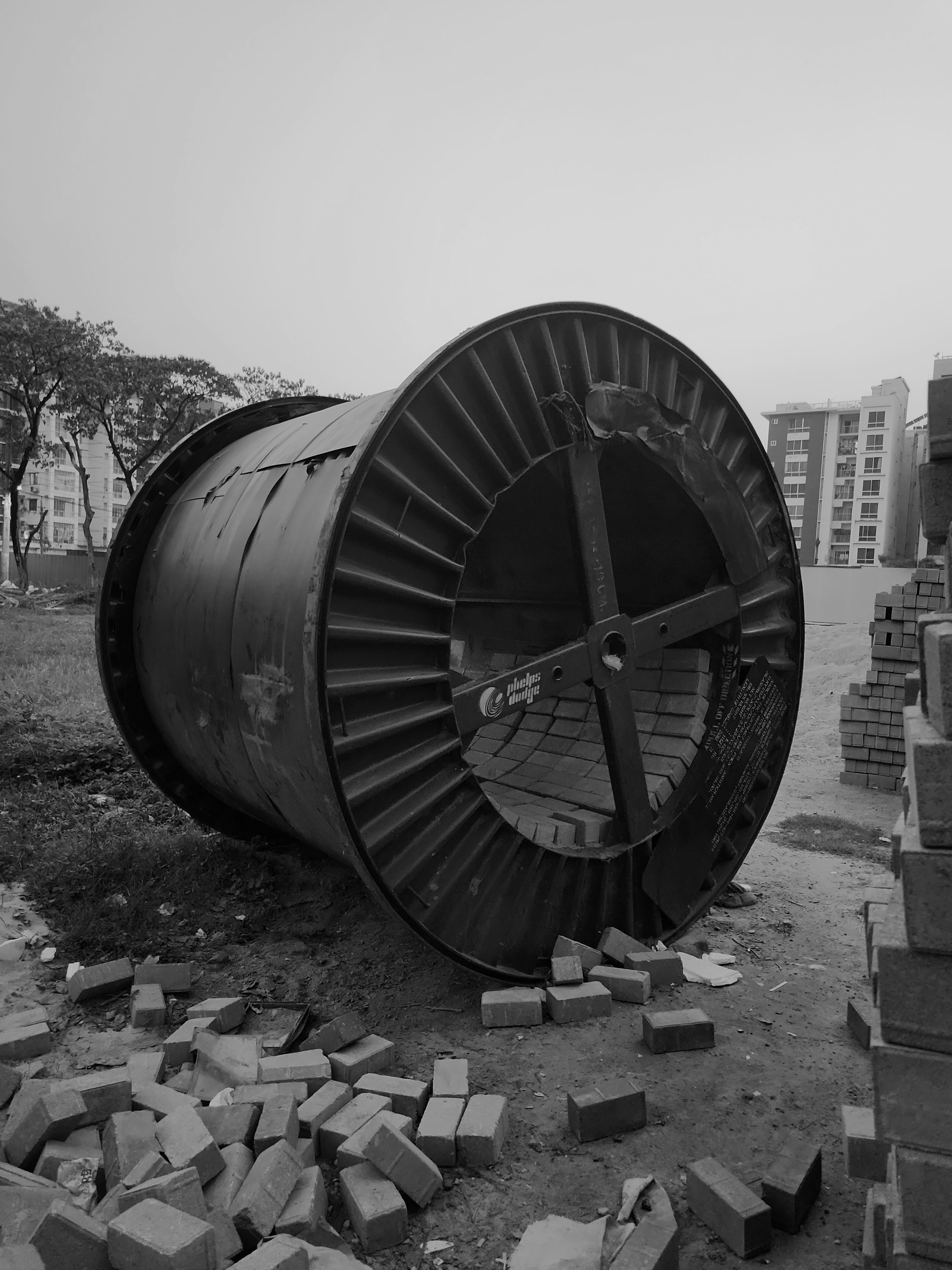 The Silent Coil: A Giant Spool Resting Among Bricks on a Construction Site
