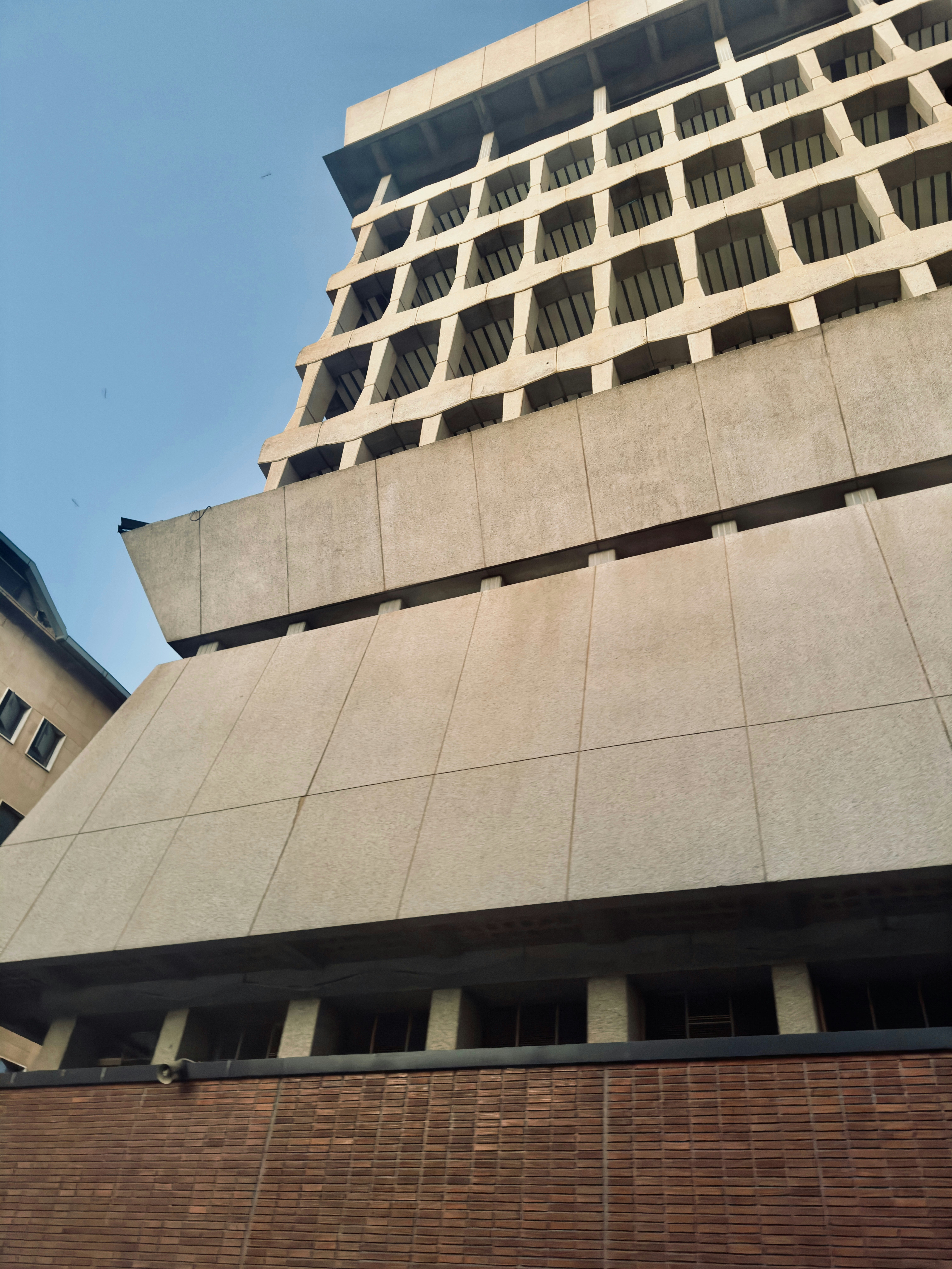 Modernist building showcasing a unique layered facade with geometric patterns against a clear blue sky.