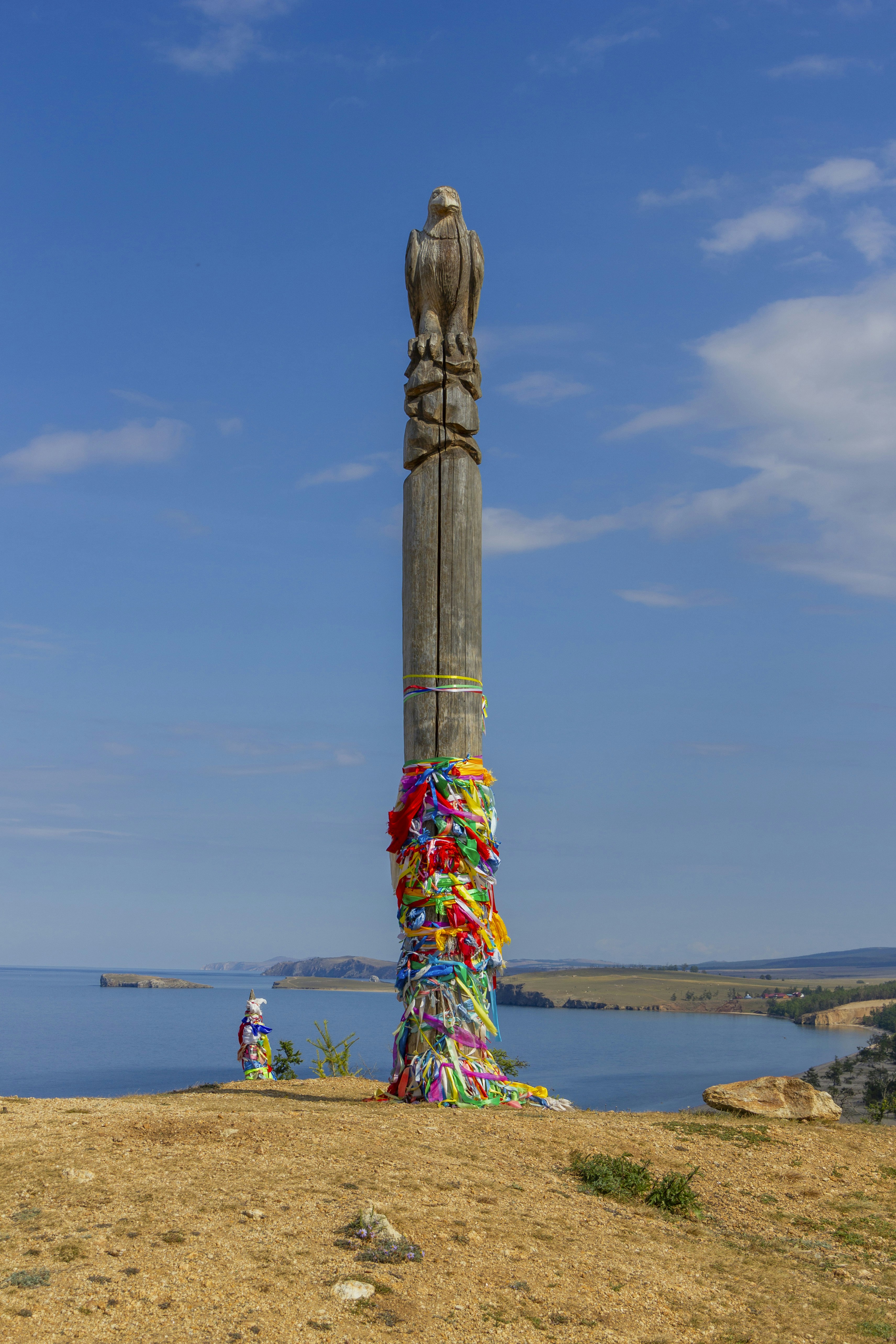 Ribboned Sentinel by the Sea: A Weathered Totem Reaching Above the Dunes