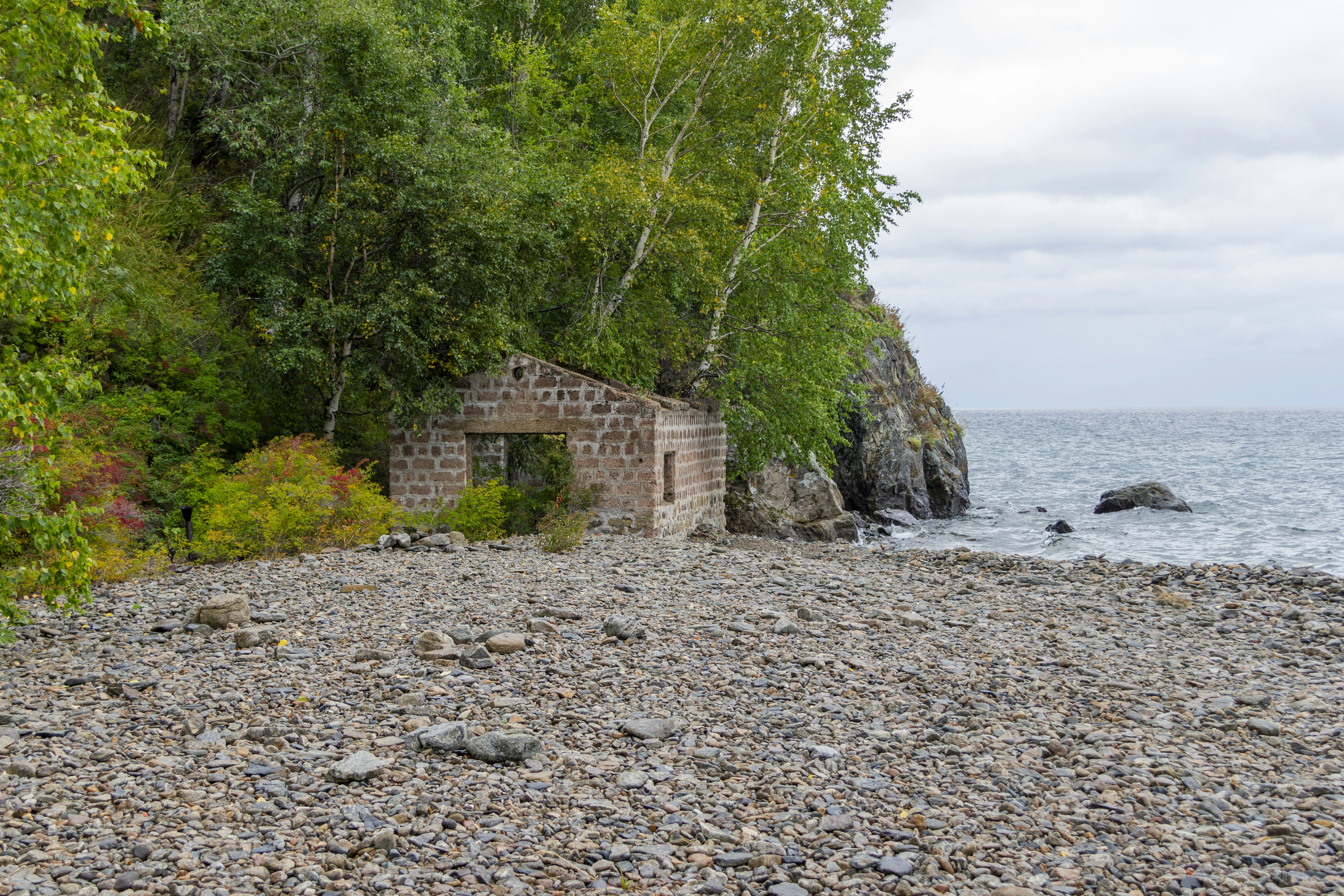 Stone Shelter on a Pebble Beach Fringed by Pines
