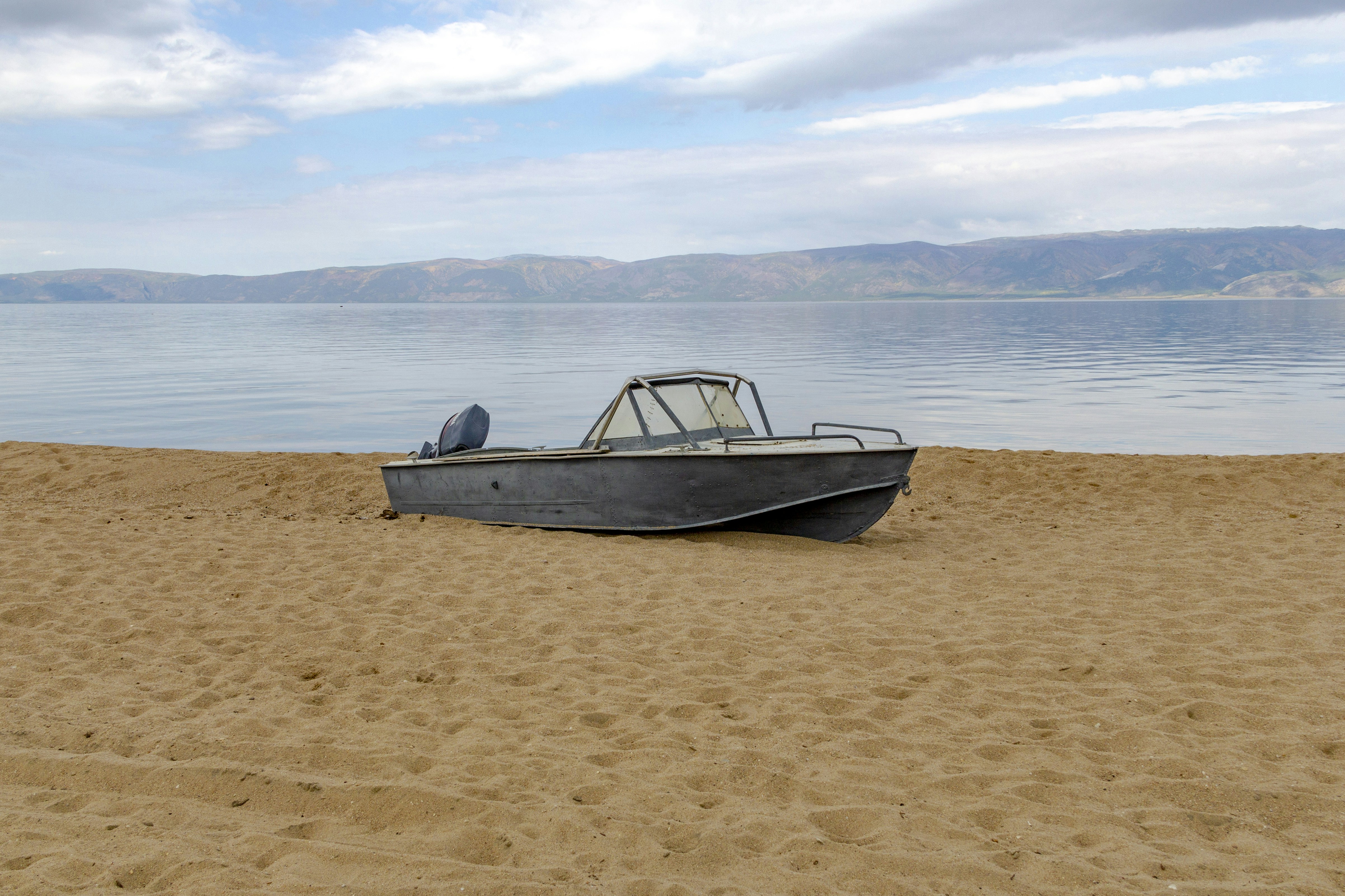 Harbor Silence: A lone motorboat rests on a sunlit lakeshore