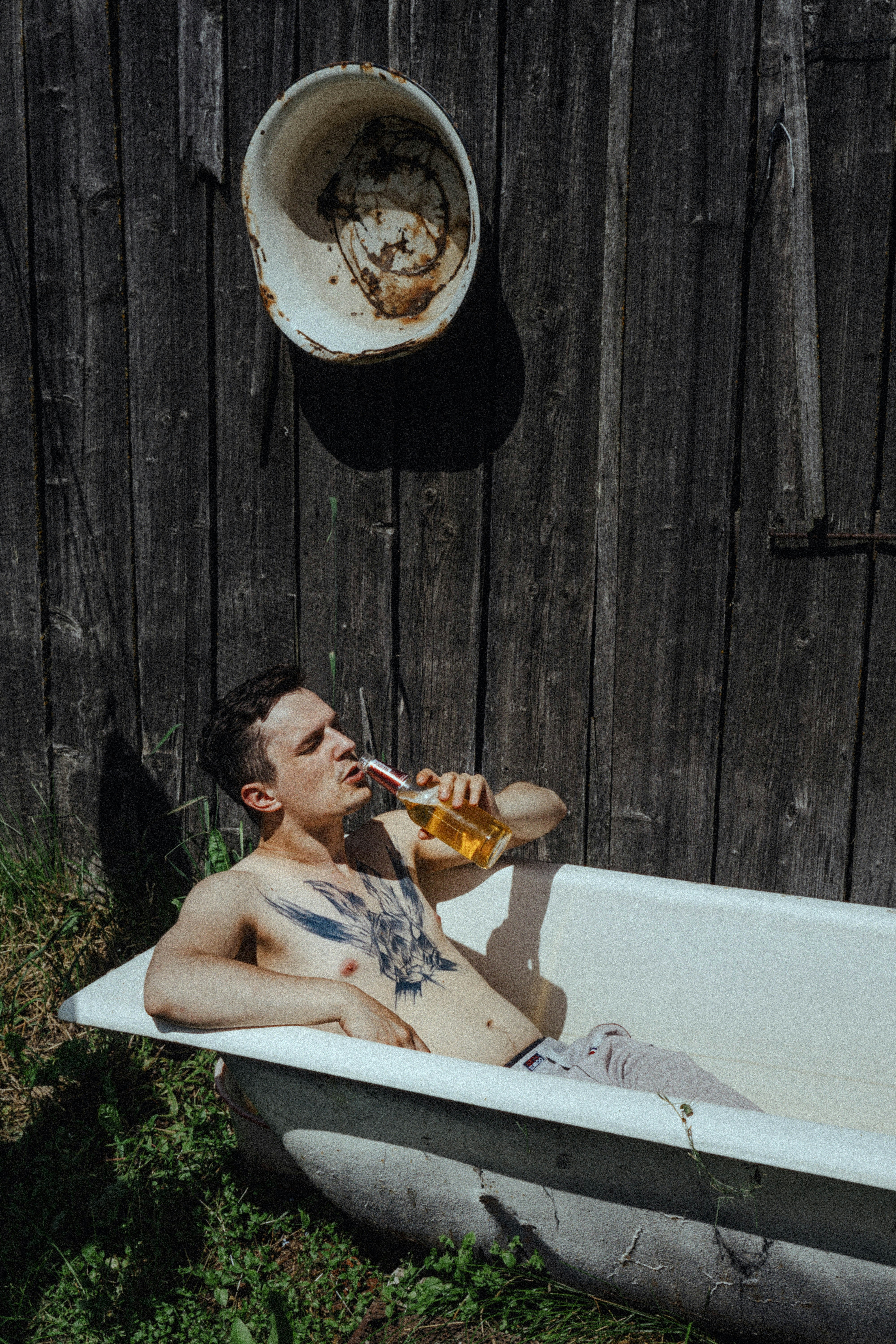 Sunlit Reckless Retreat: Beer in a Bathtub by a Weathered Wall