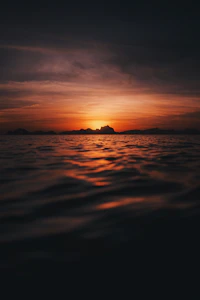Horizon Glow: Sunset Over Rippling Sea and Distant Isles