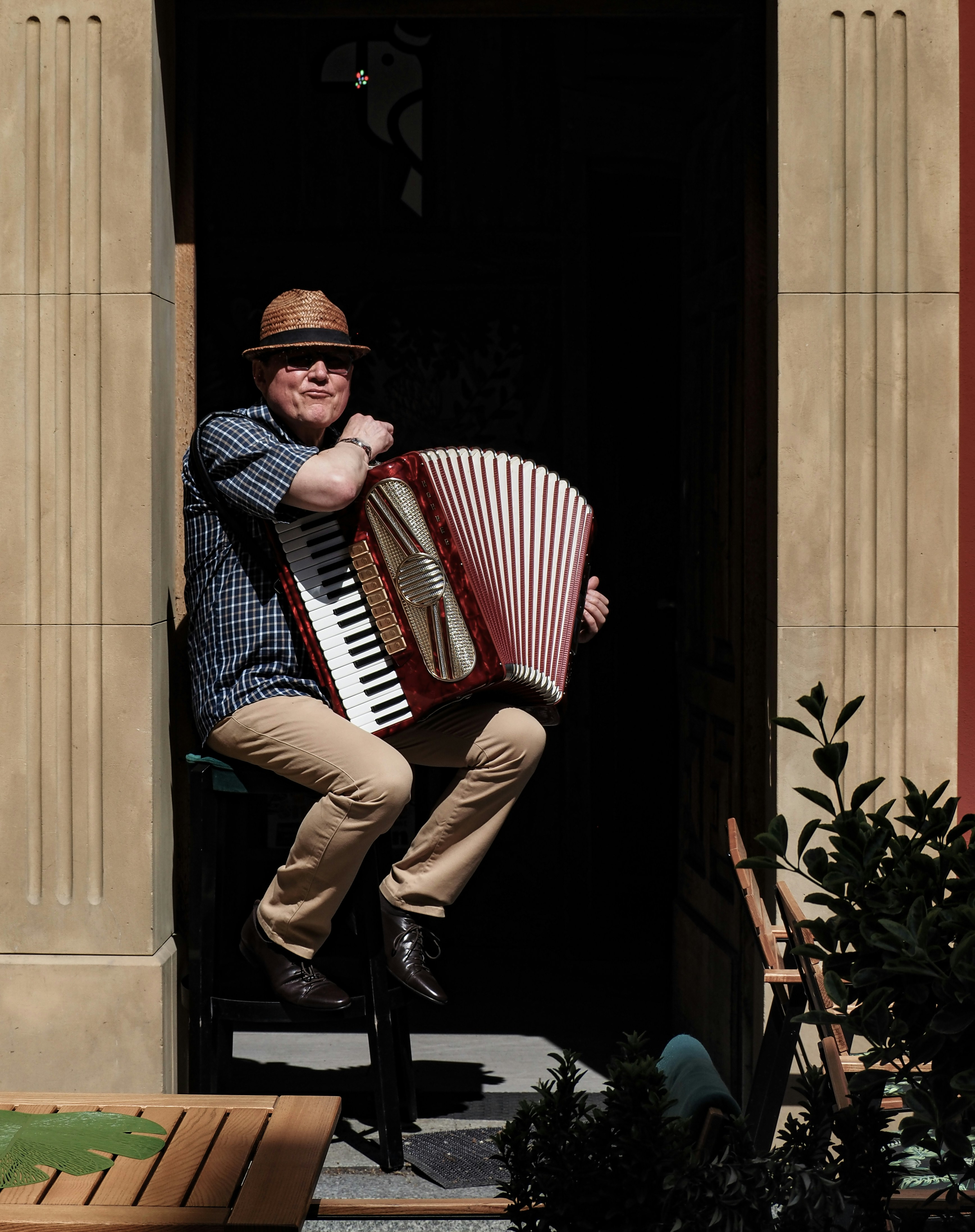 Doorway Serenade: Sunlit Accordionist in a Shadowed Entrance