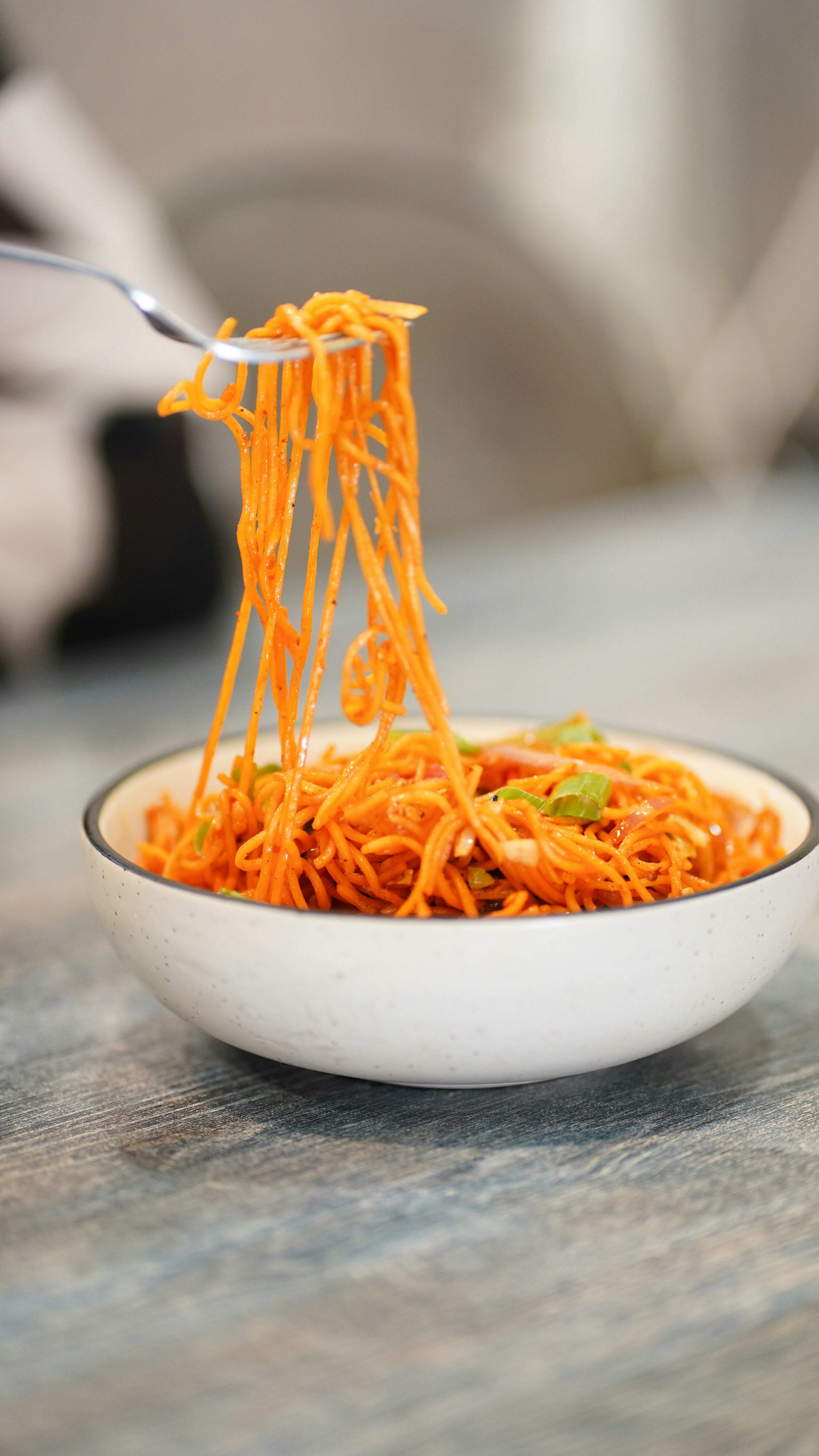 Twirled Tango: Orange Spaghetti on a Fork over a Quiet Bowl