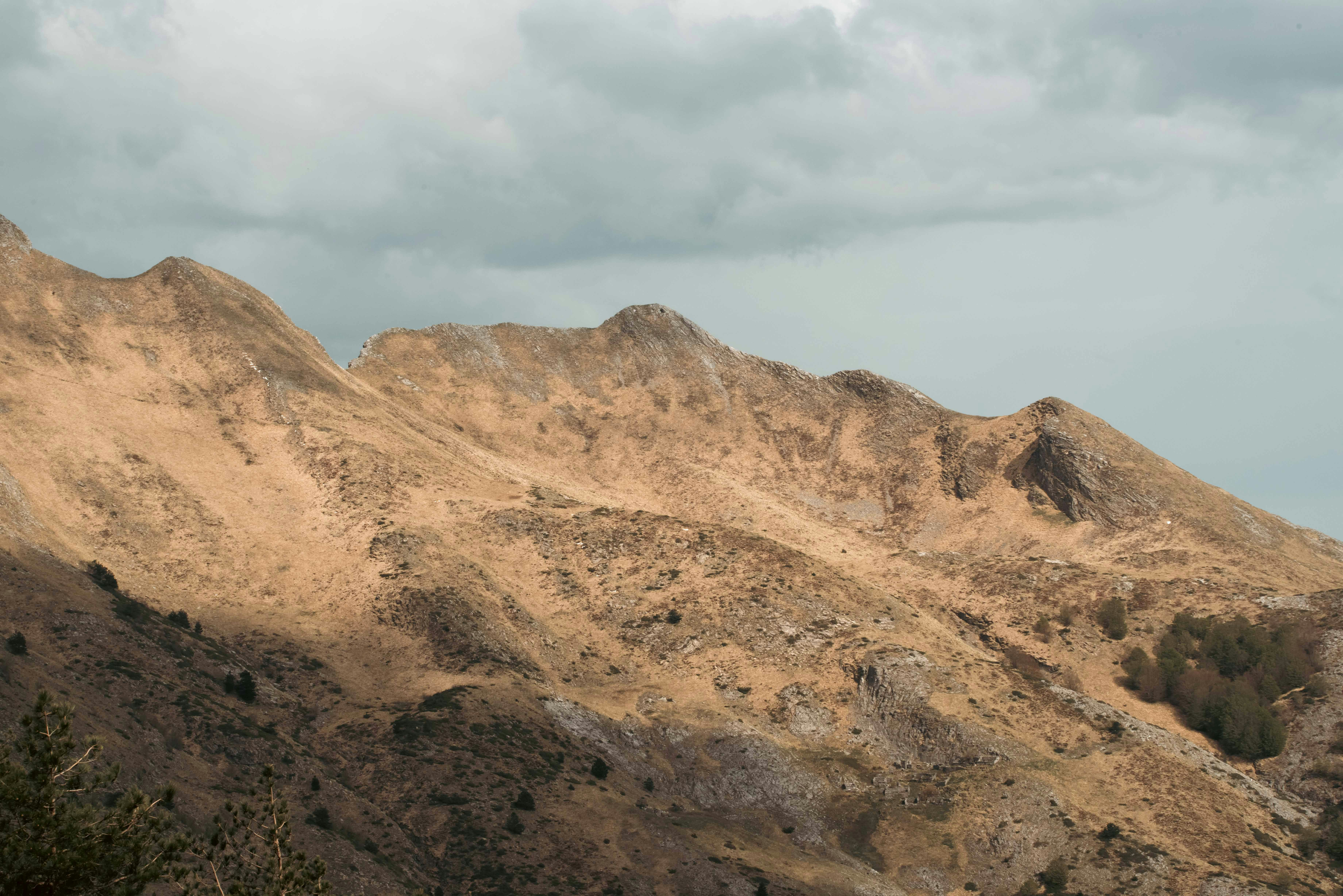 Rolling hills with golden hues under a cloudy sky.