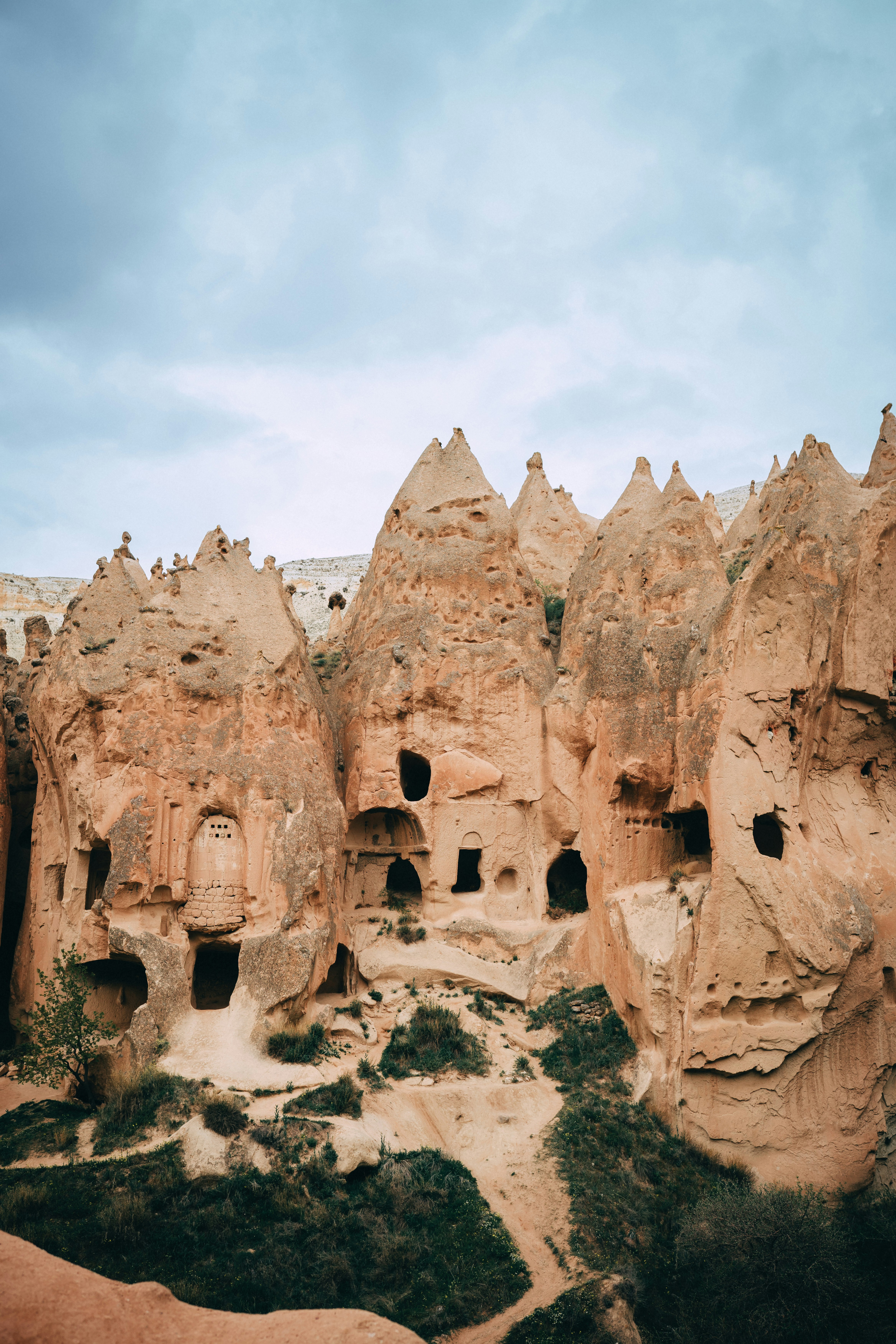 Unique rock formations with carved-out dwellings in a rugged landscape, showcasing the interplay of nature and human habitation.
