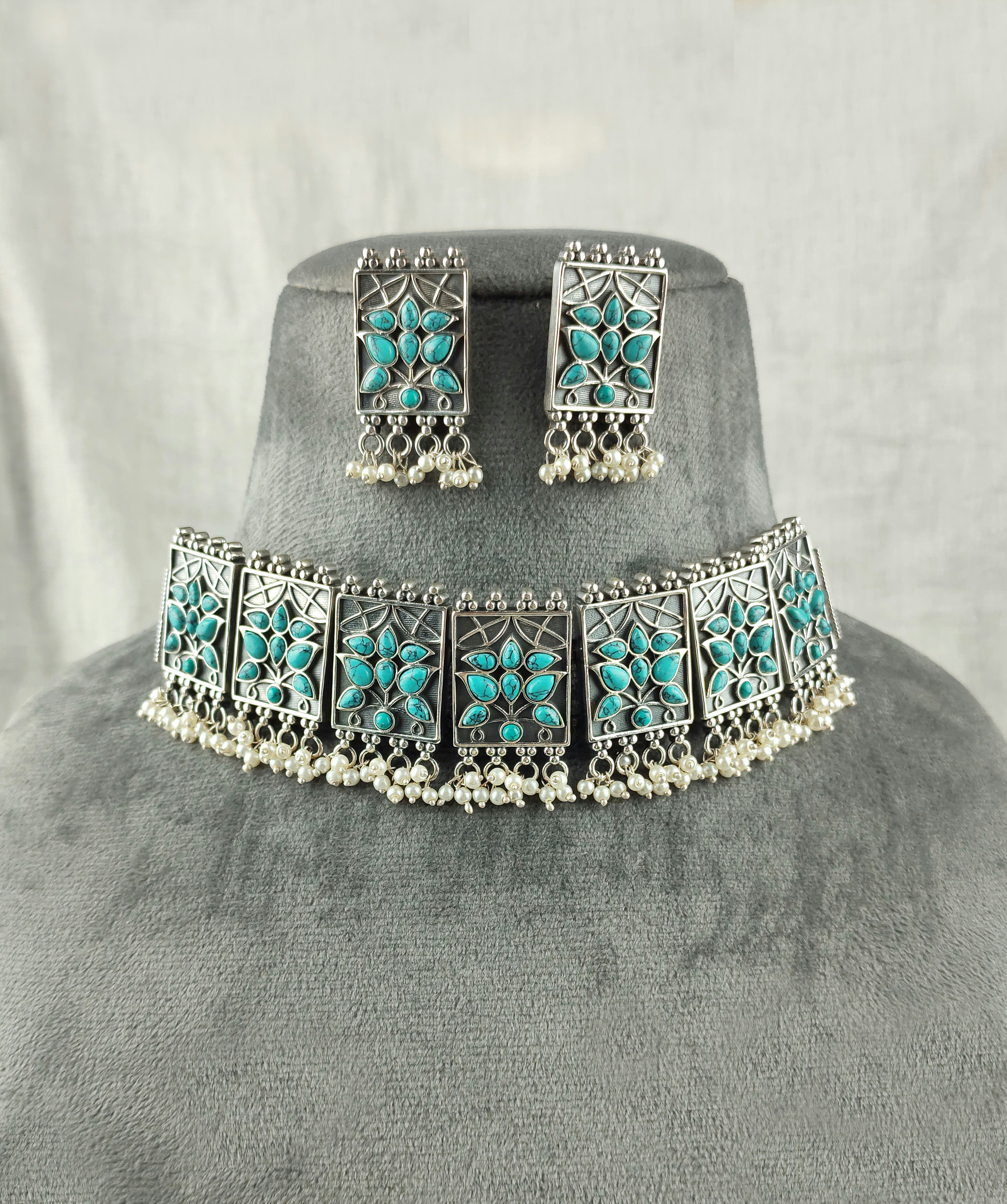 The Silver traditional Choker Necklace you described sounds stunning! The combination of Turquoise stones, along with pearl clusters, must create a truly royal and elegant look. The fact that it is adjustable makes it versatile and suitable for different neck sizes and outfit styles. Handcrafted from original 92.5 silver with Traditional Black oxidized Polished finish adds to its appeal and ensures its quality. It sounds like an attractive piece that can elevate any outfit for various occasions.