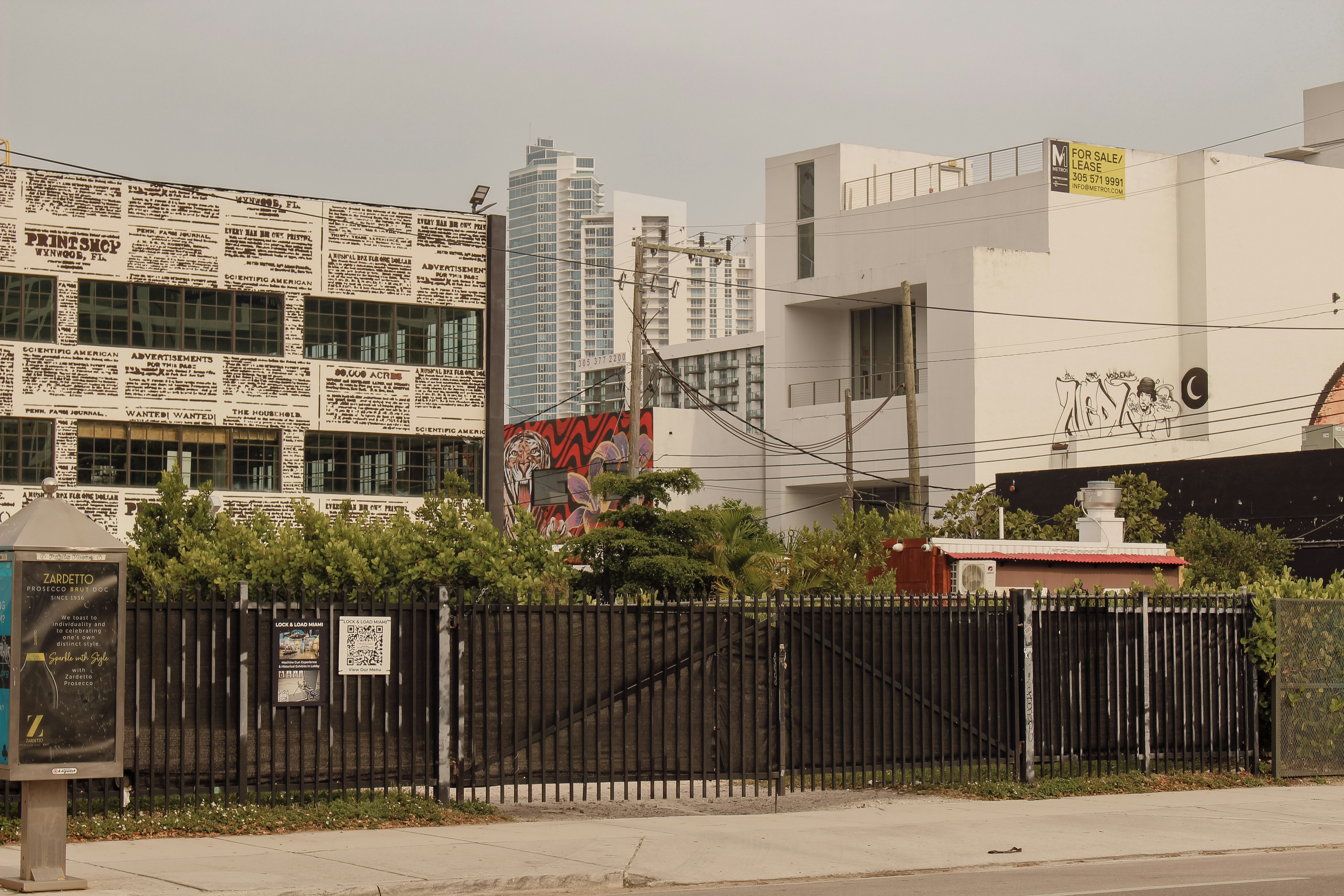 A fenced in area next to a street with buildings in the background ...
